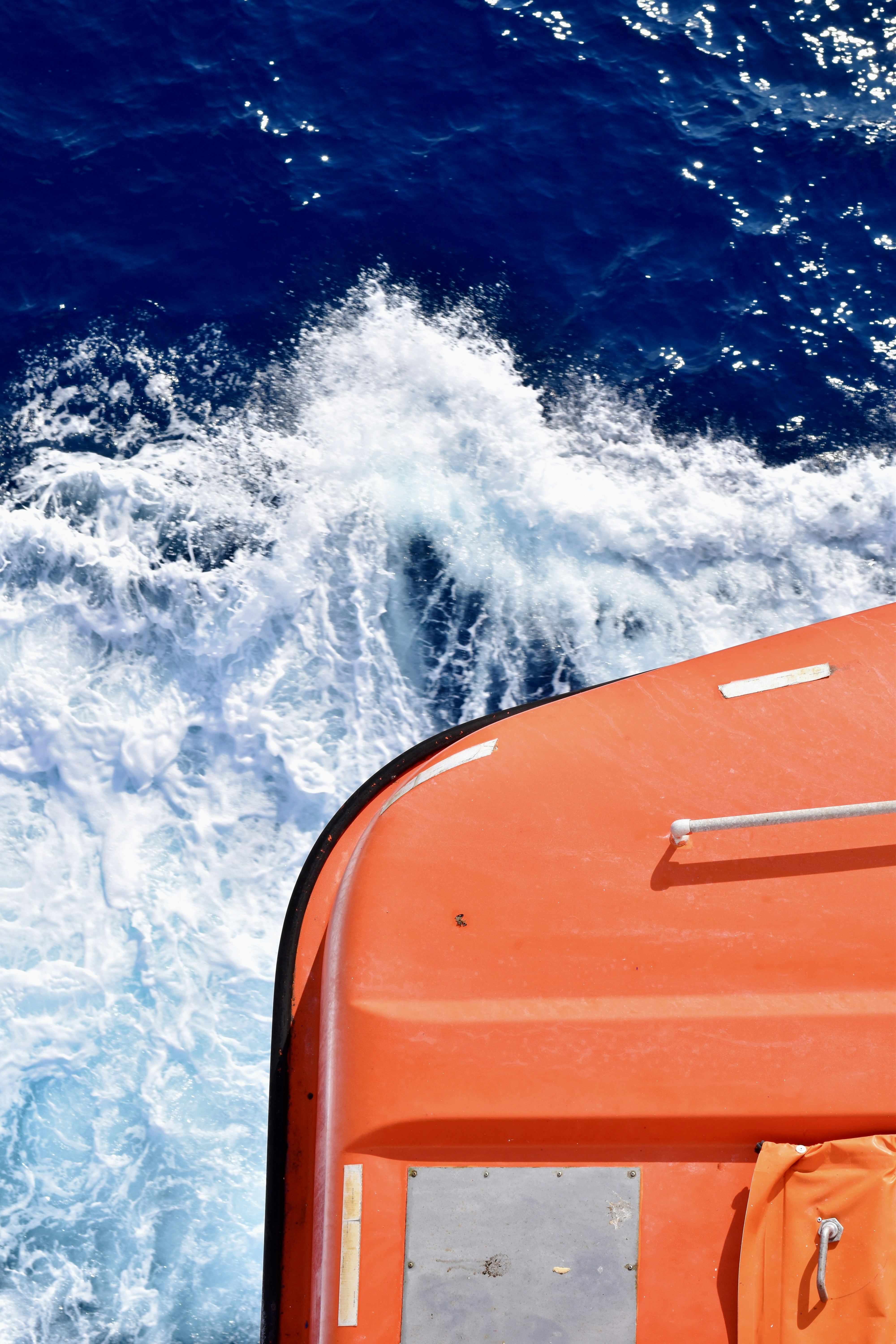 Orange Lifeboat Cut Across a Blue Wake