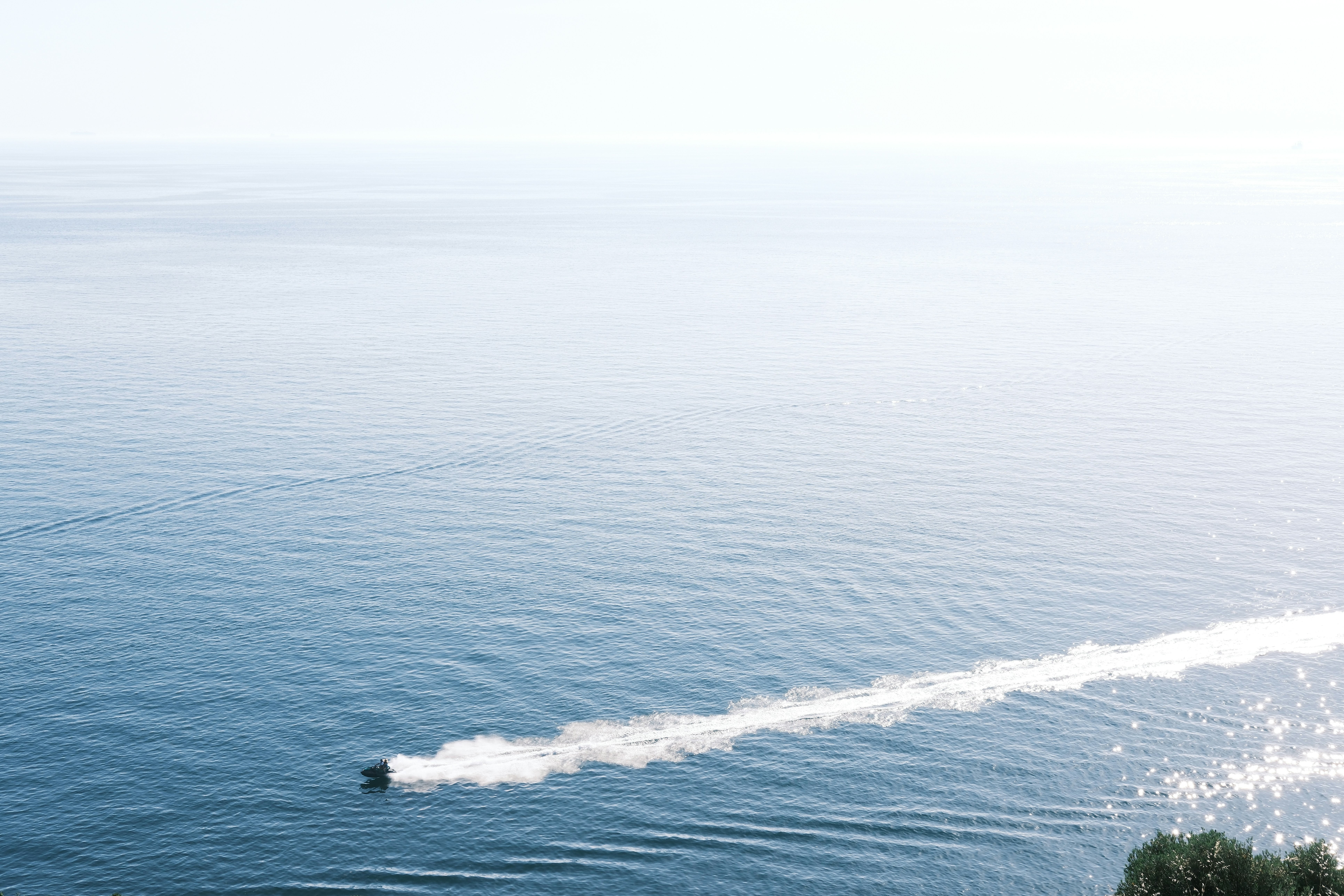 Jet Trail Across a Calm Sea: Glinting Wake in a Quiet Horizon