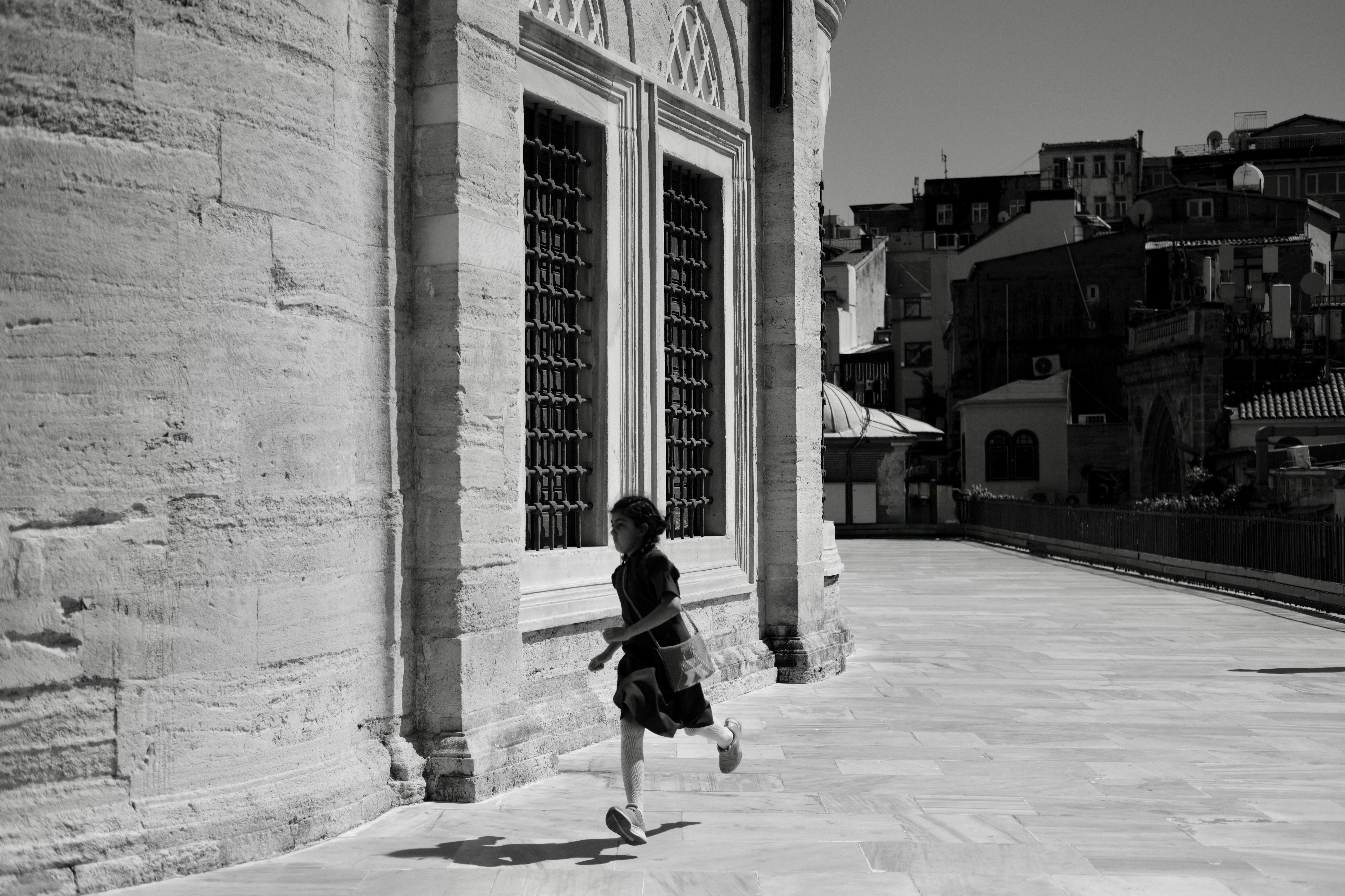 A lone runner in grayscale across sunlit stone at a historic site
