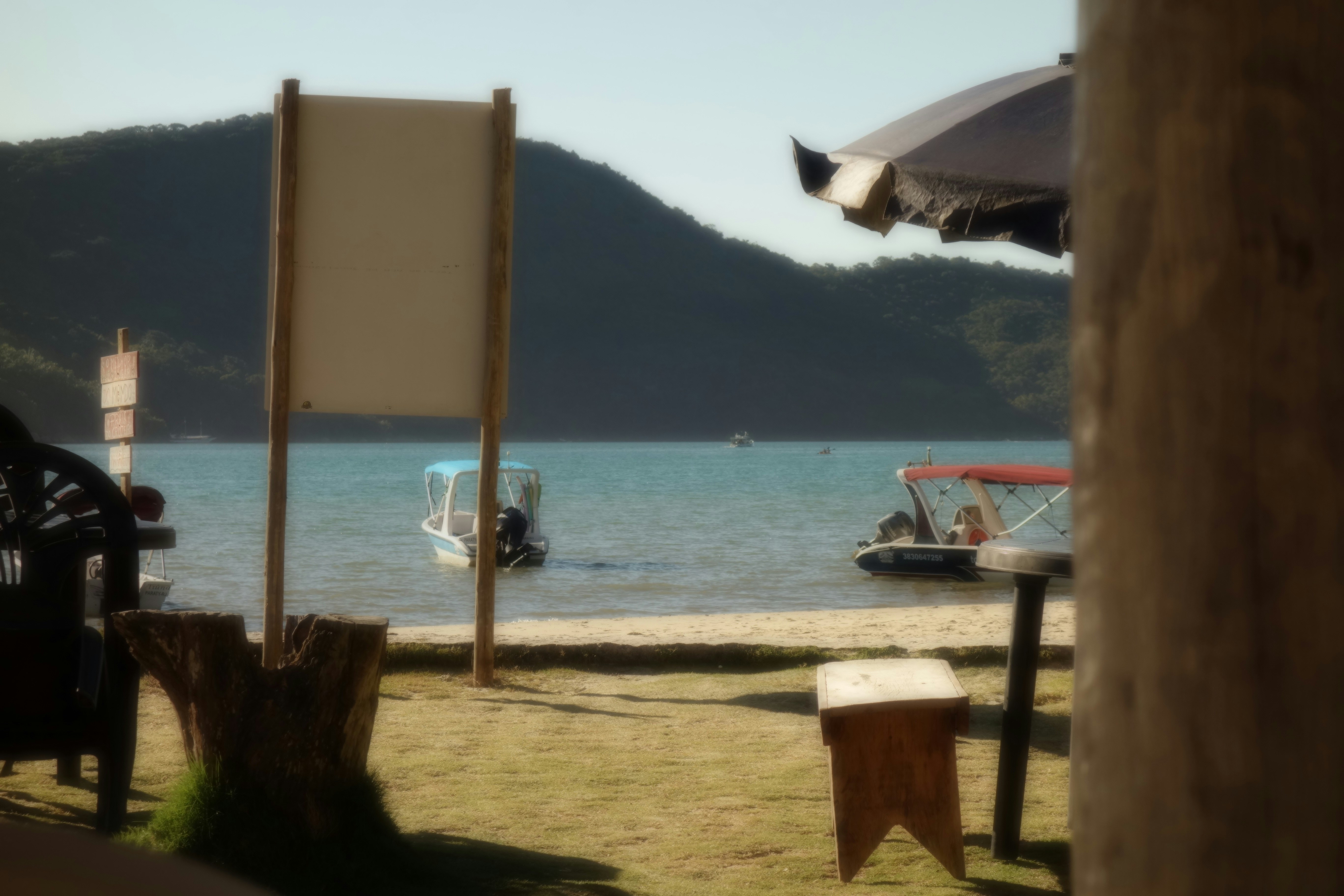 Beachside Quiet: Boats Rest at Shore Under Distant Hills