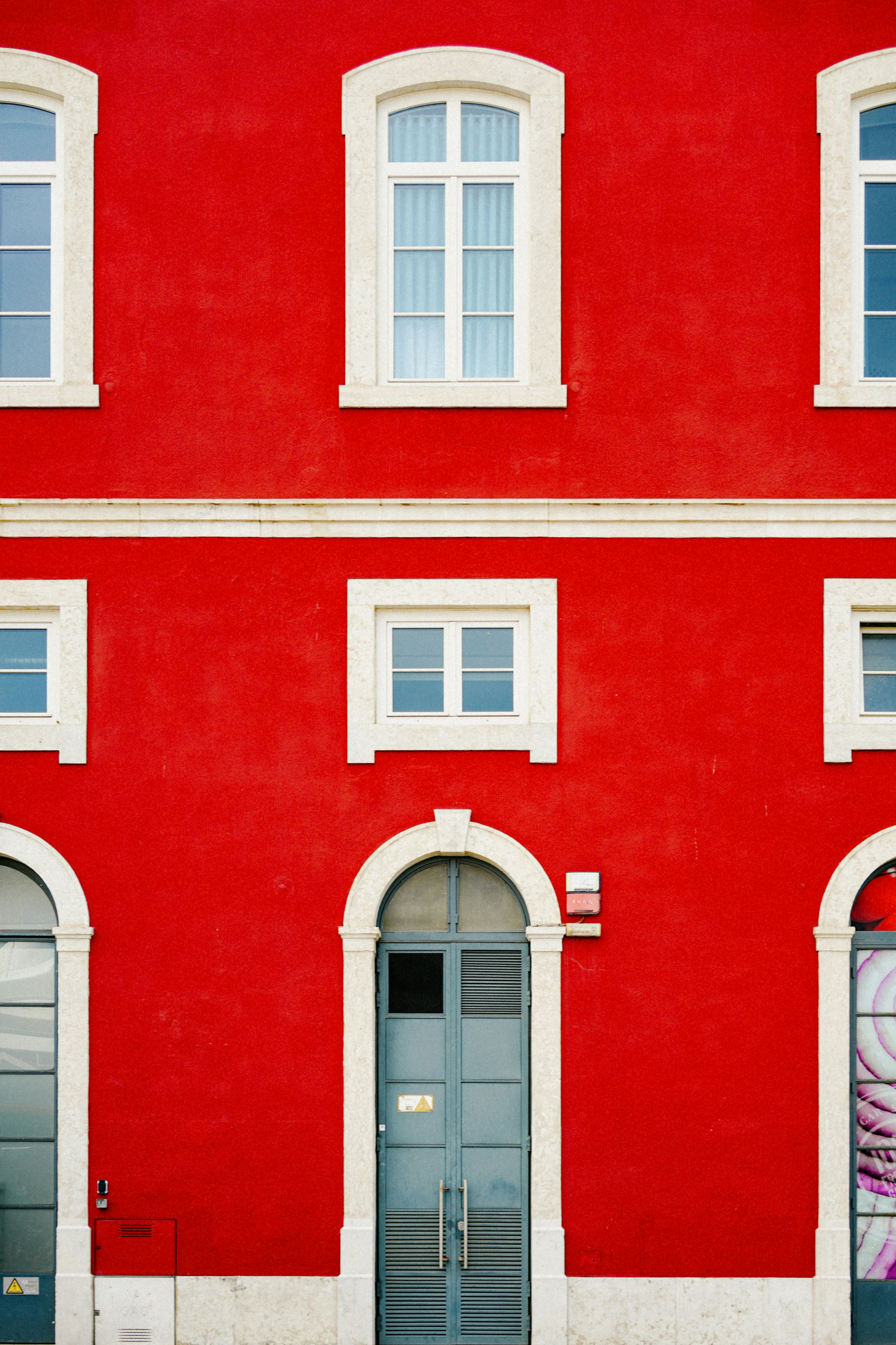 Red Facade Symphony: A Symmetrical Streetfront with Pale Arches