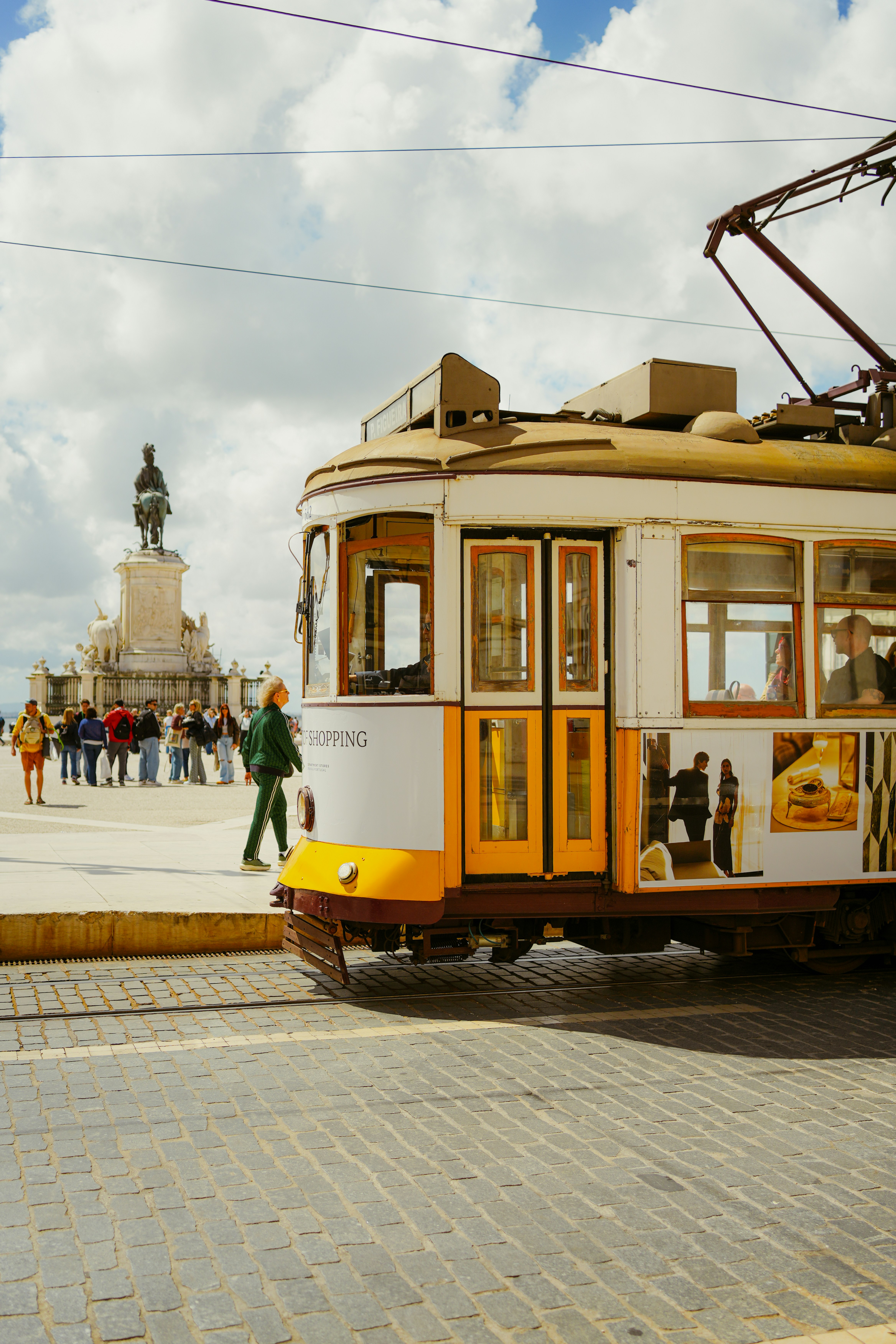 Yellow Tram on a Sunlit Square with Statue Backdrop