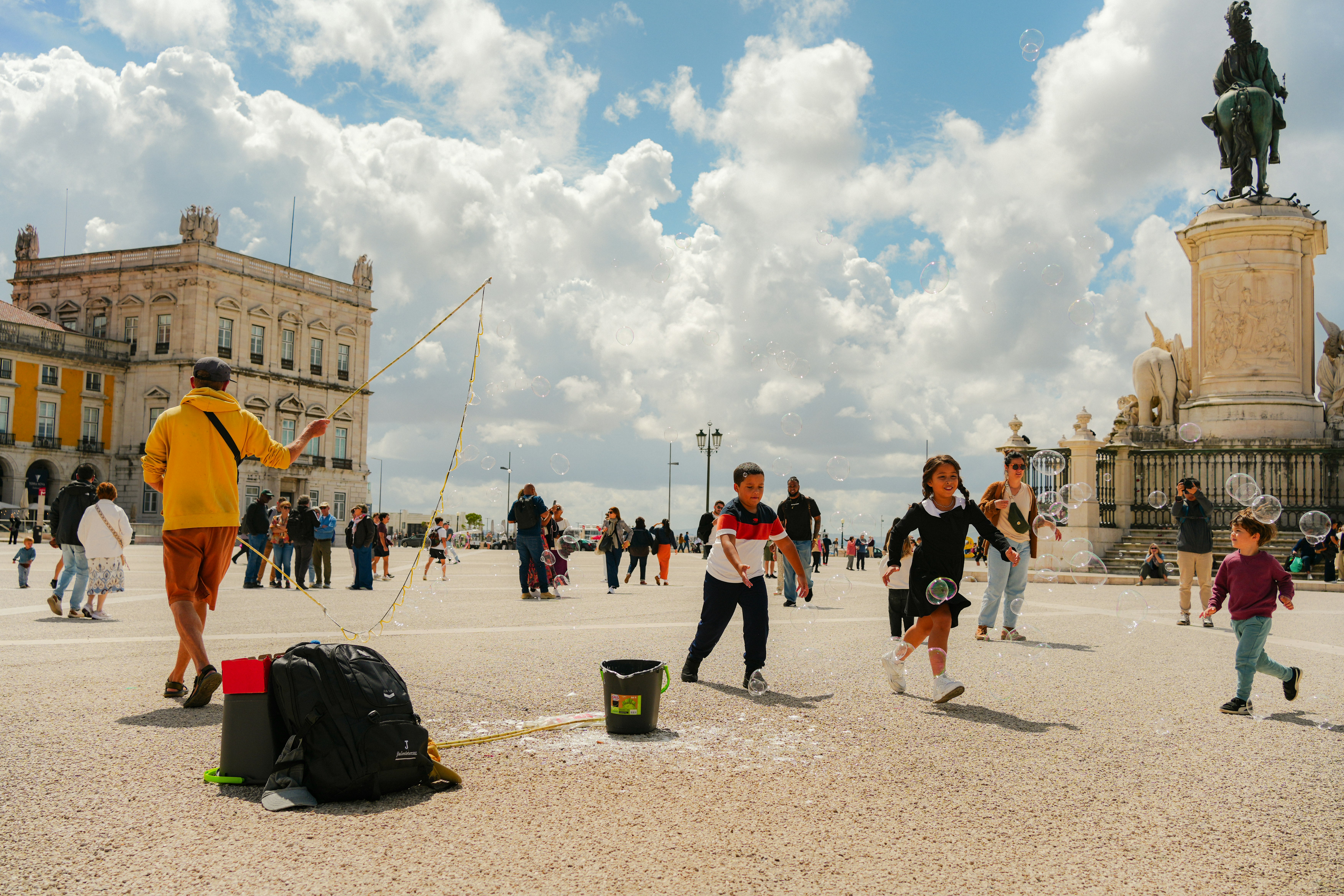 Lively Plaza: Children Chase a Splash of Water Under a Statuesque Square