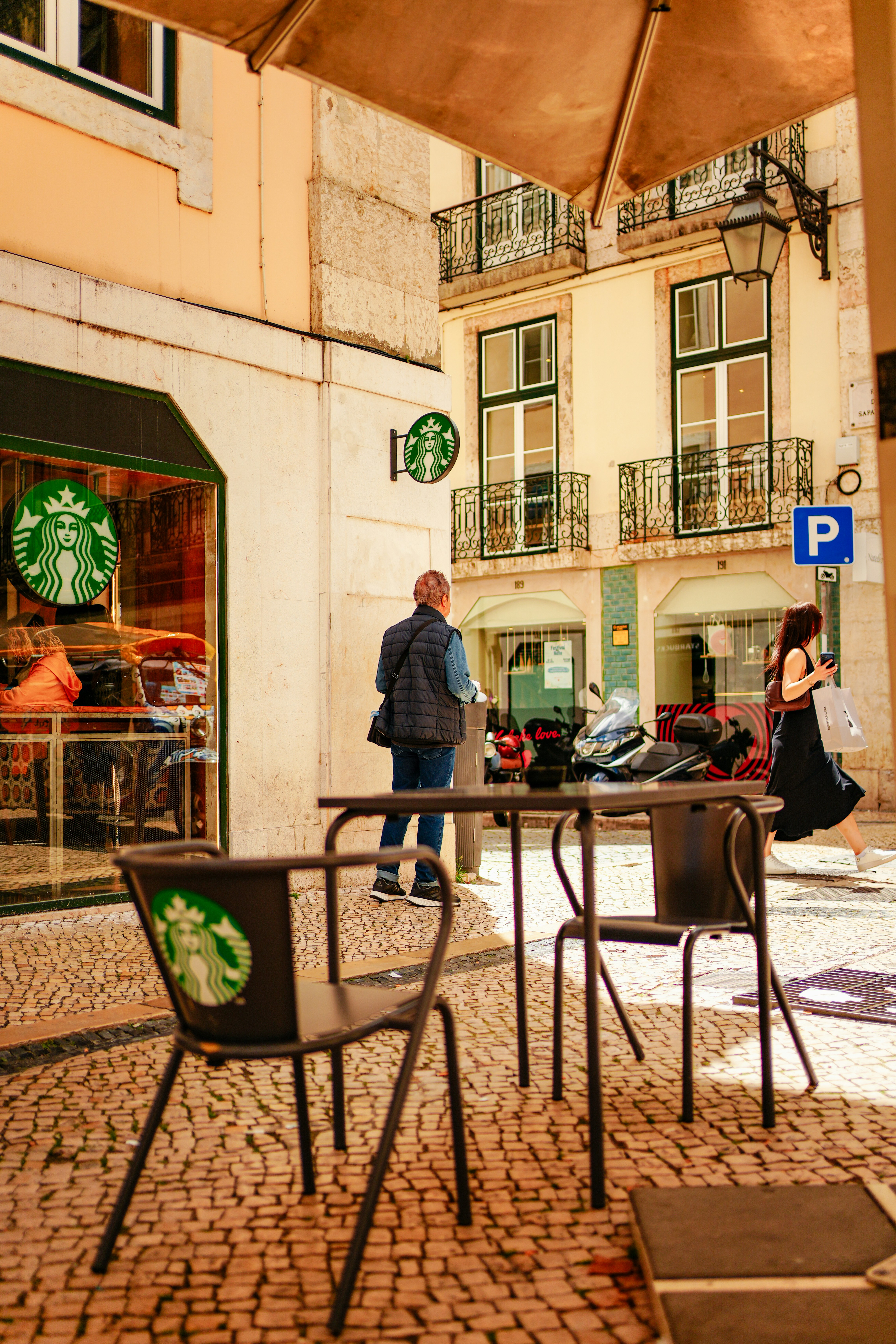 Street Café Quietude: An Urban Moment by Starbucks and Sunlit Facades