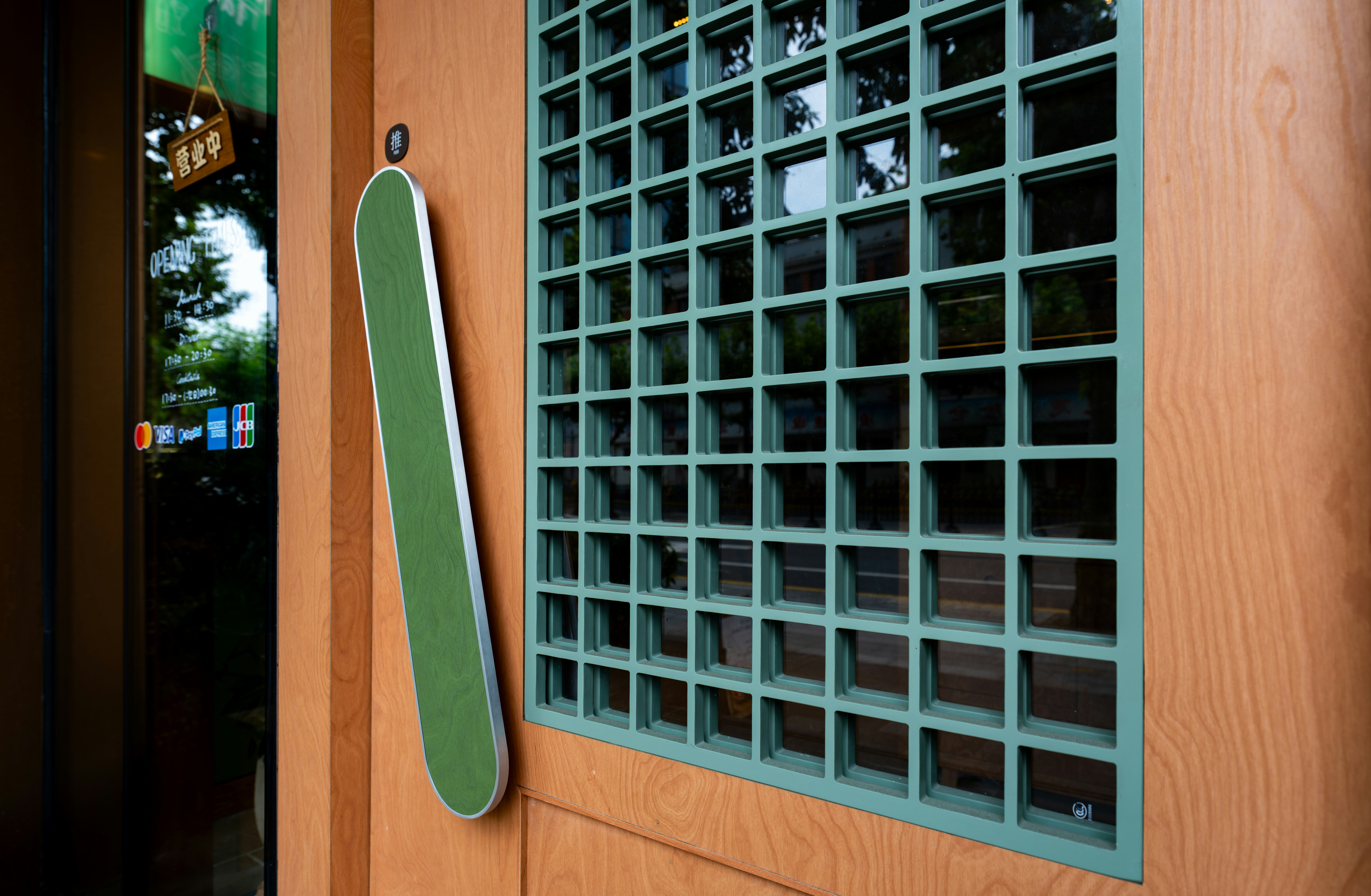 Green Skateboard Leaning by a Grid Window on a Wood Door