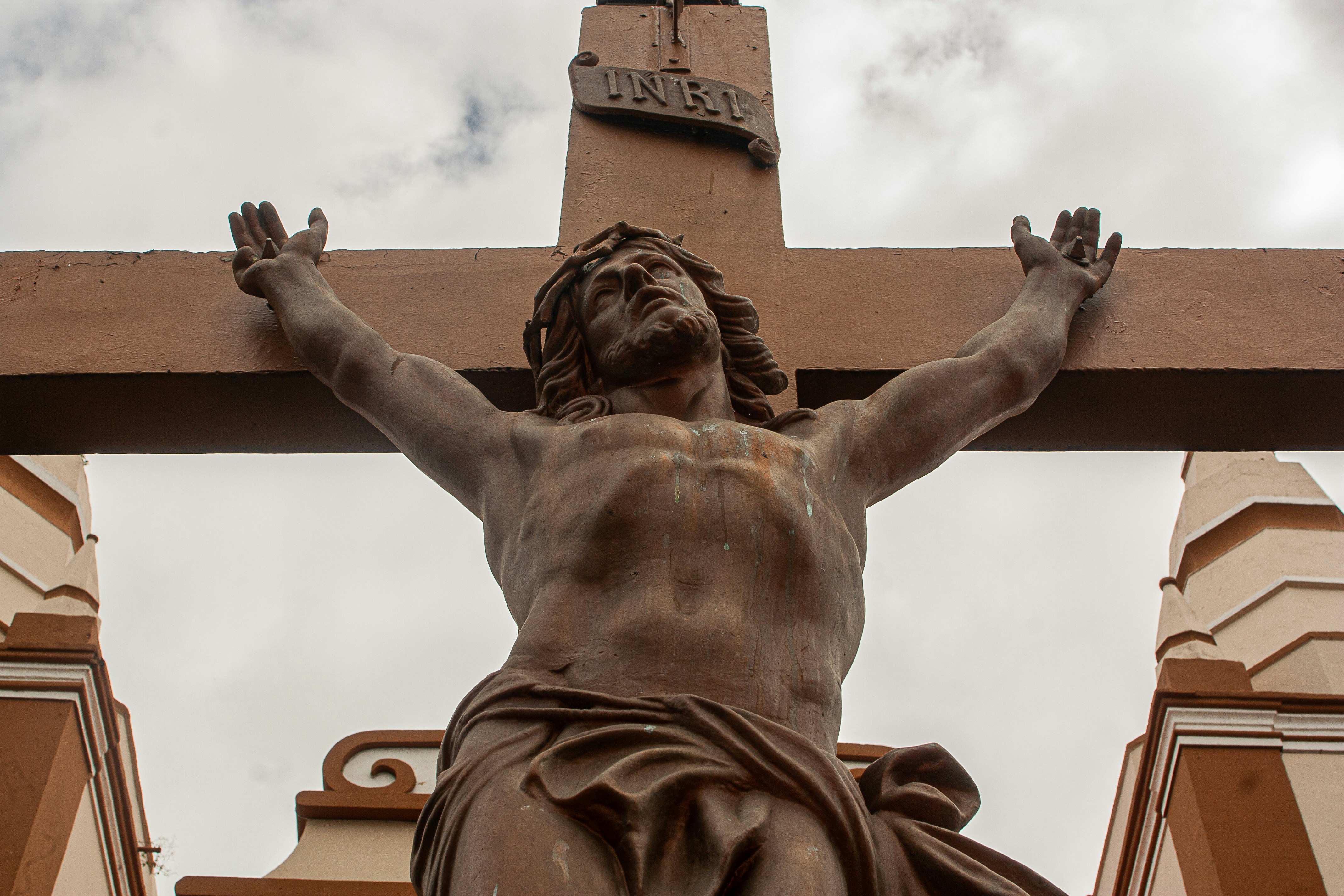Cruciform Reverence: A close-up of the crucified statue against a stoic architectural backdrop