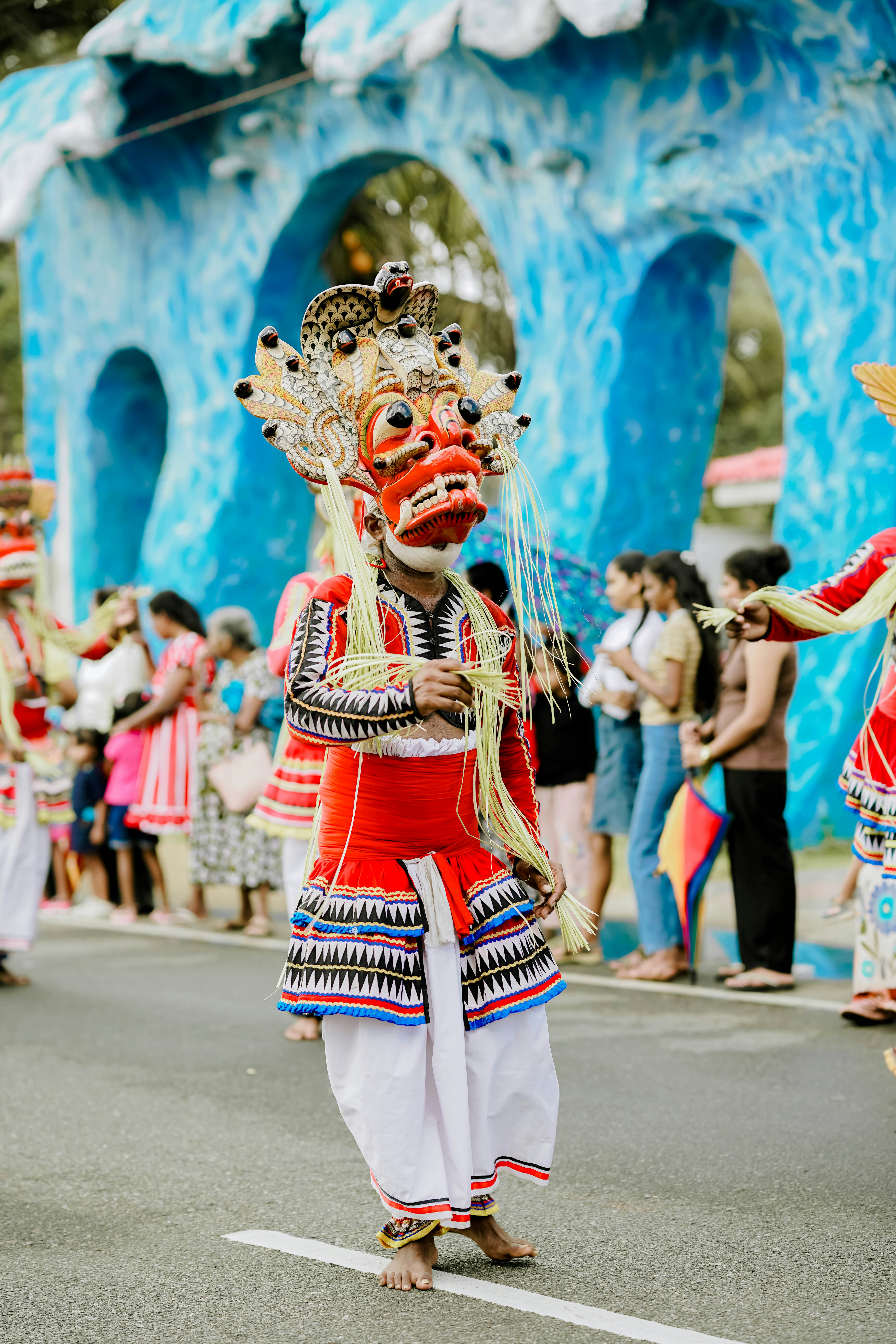 Masked dance of color: a ceremonial performer strides through the parade
