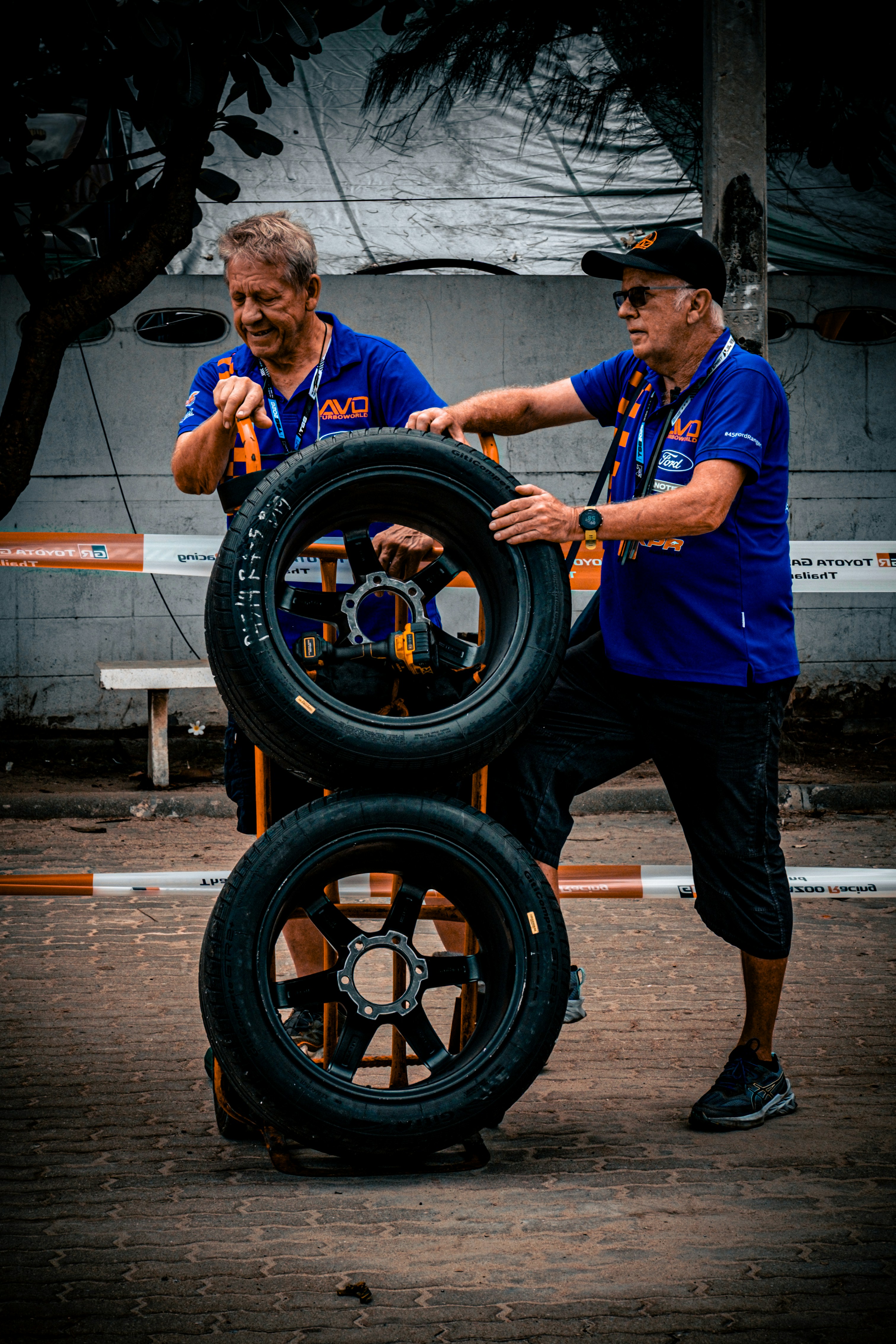 Teamwork in Tire Change: Two Mechanics Maneuver a Portable Wheel Station