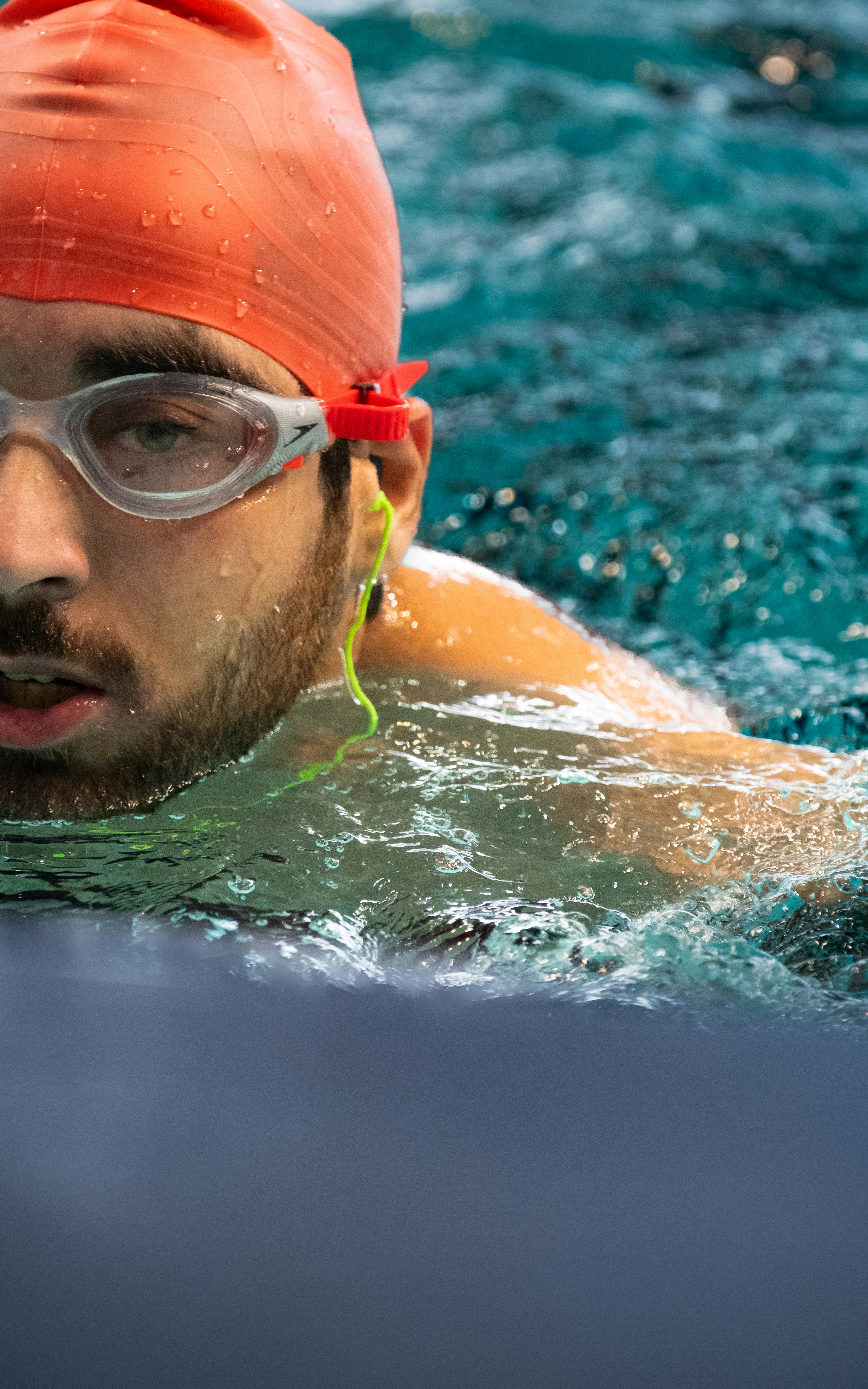 Orange Cap, Clear Gaze: Focused swimmer mid-breath