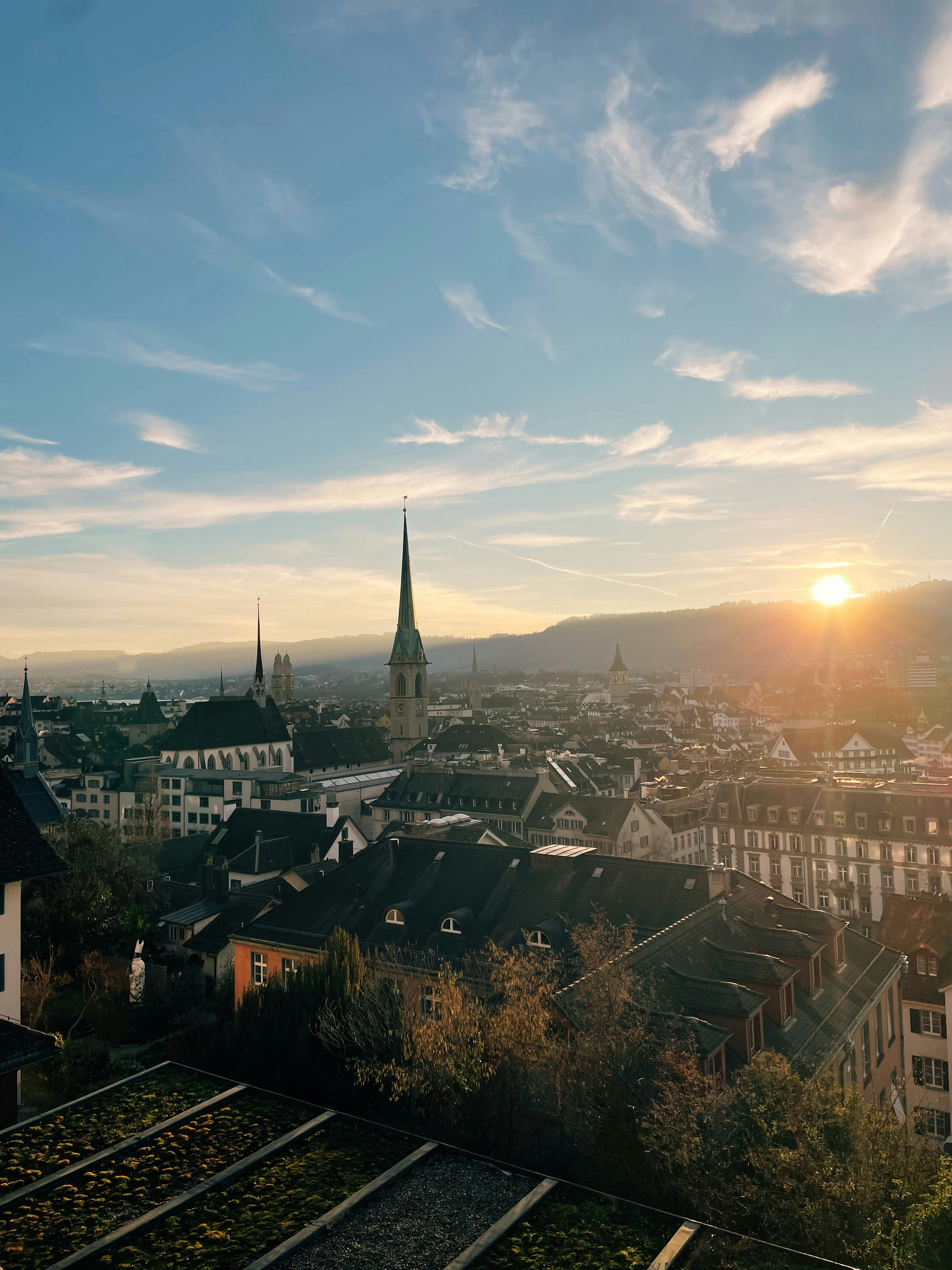 Sunlit Spire Over a European Rooftop Townscape at Dusk