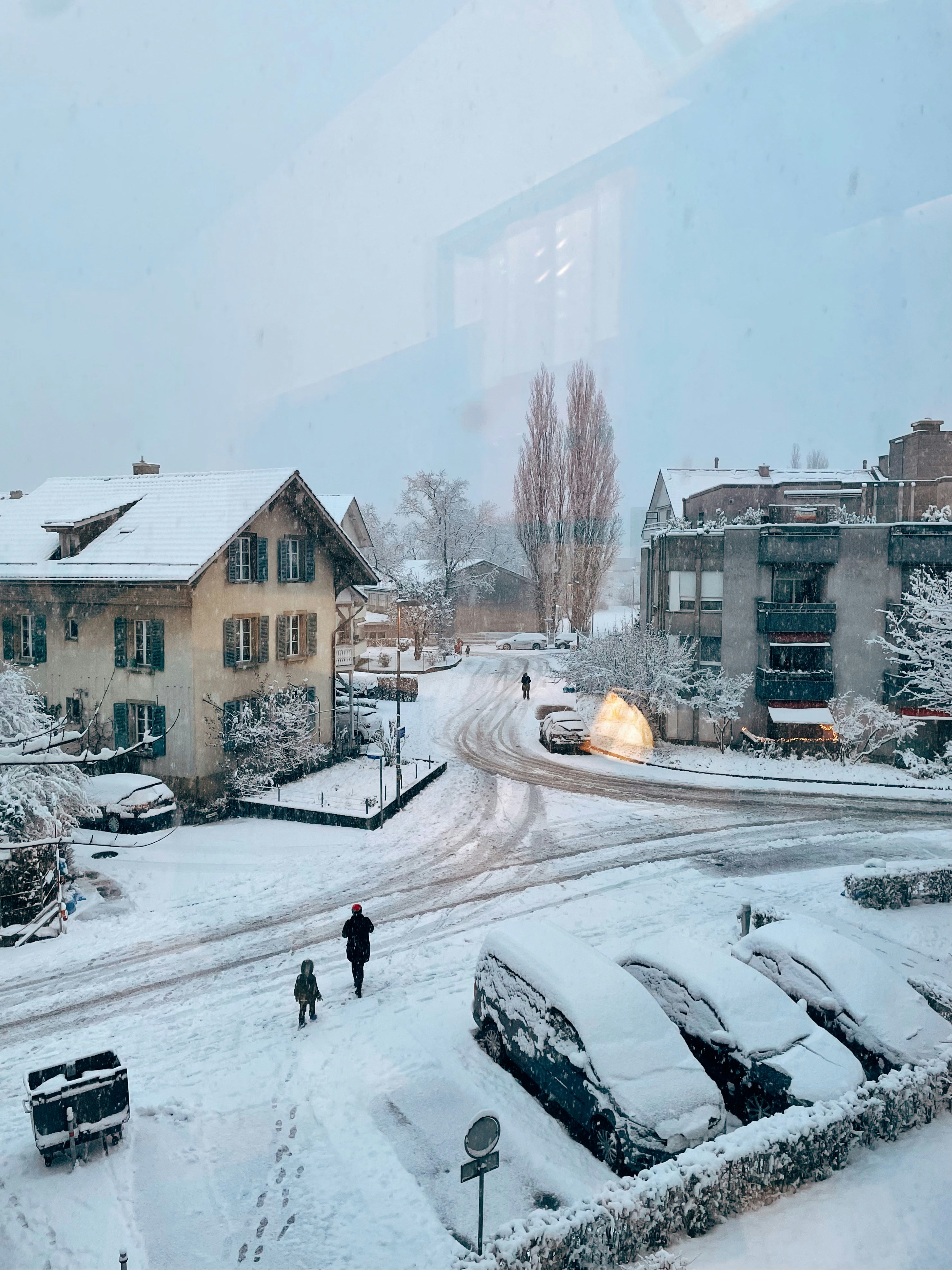 Snow-Covered Street Aglow: Families and Lantern in a Quiet Swiss Village