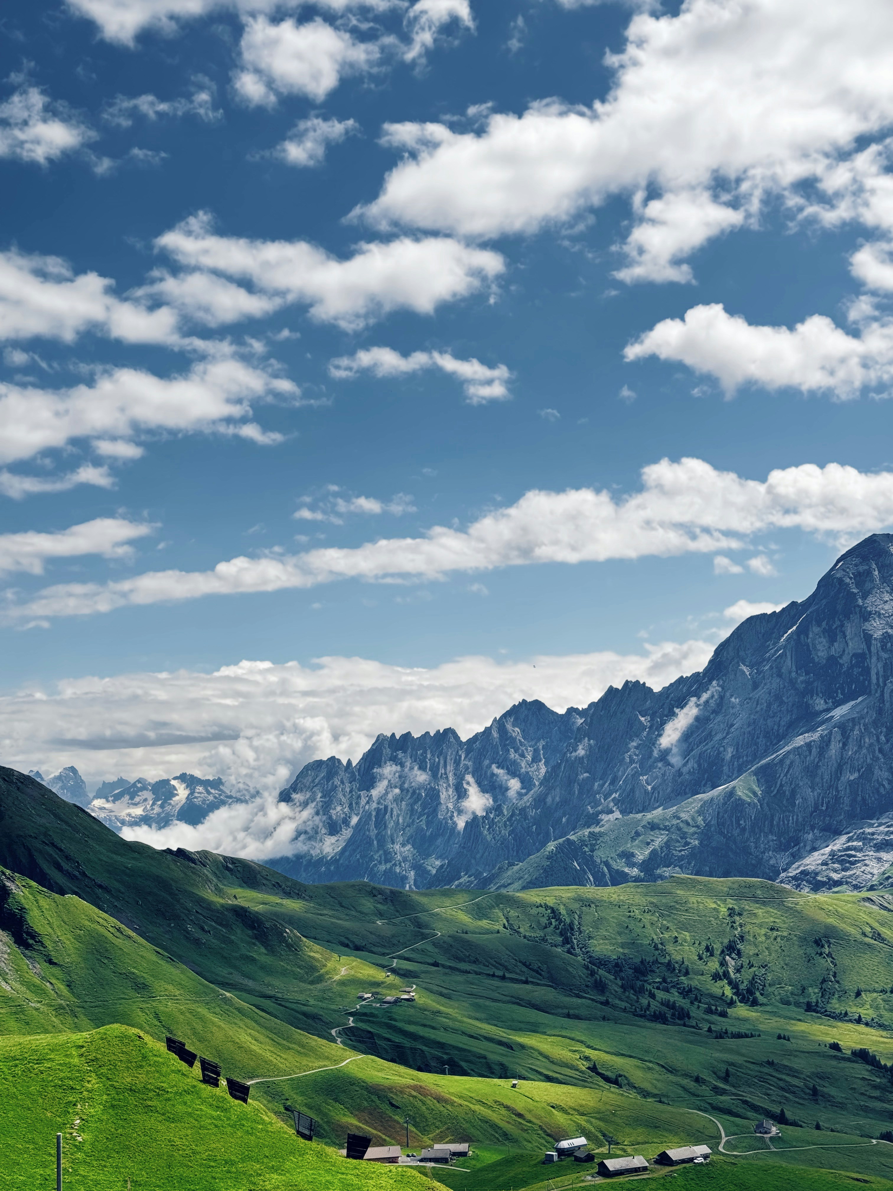 Green Valley Road Winds Through Alpine Peaks Under a Bright Sky