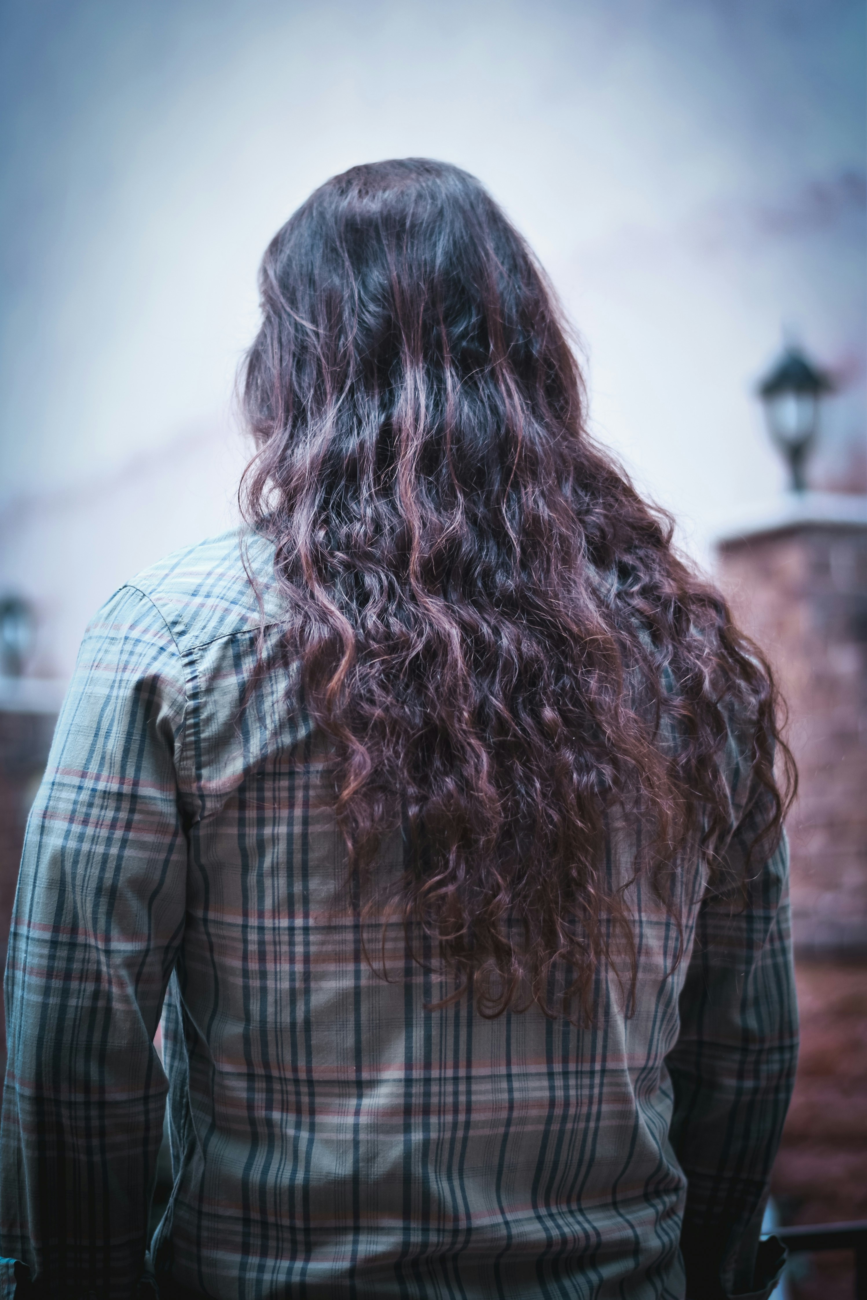 Backlit Cascade: Wavy Hair Framing a Quiet Stairwell