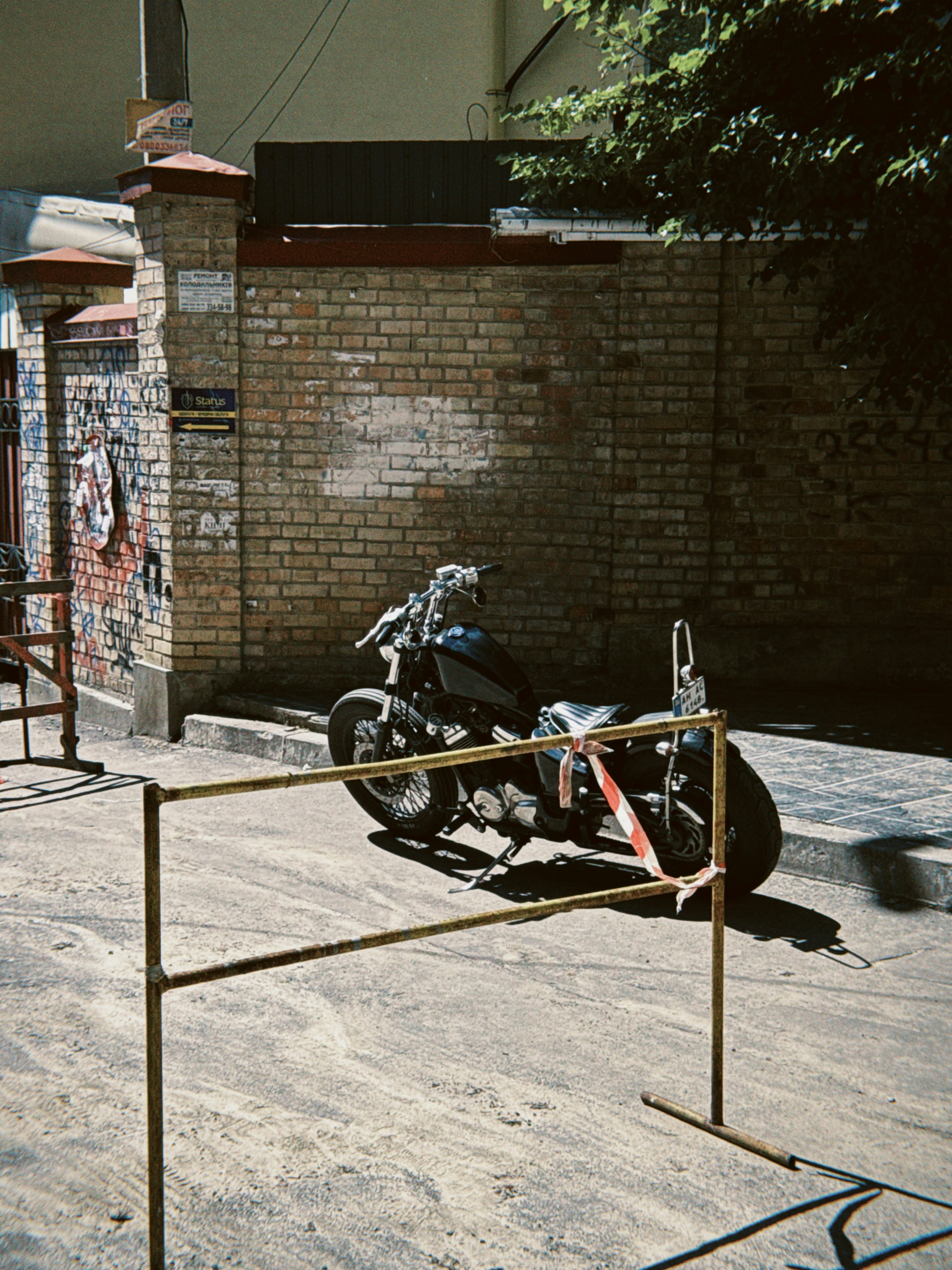 Midday Standstill: A Motorcycle Framed by Weathered Brick and Tape