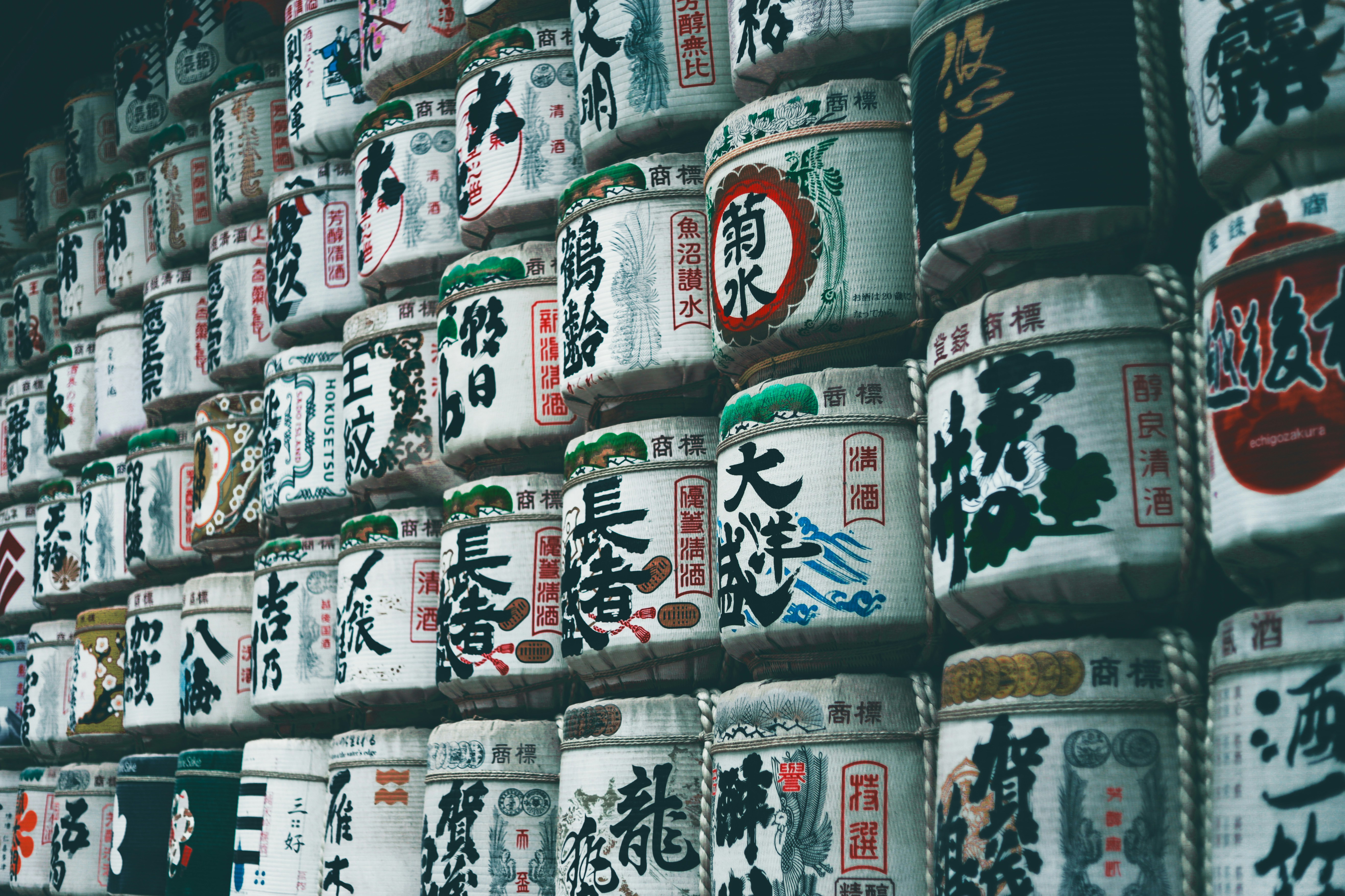 Dense wall of sake barrels with Japanese kanji labels forms a textured mosaic of patterns and colors.