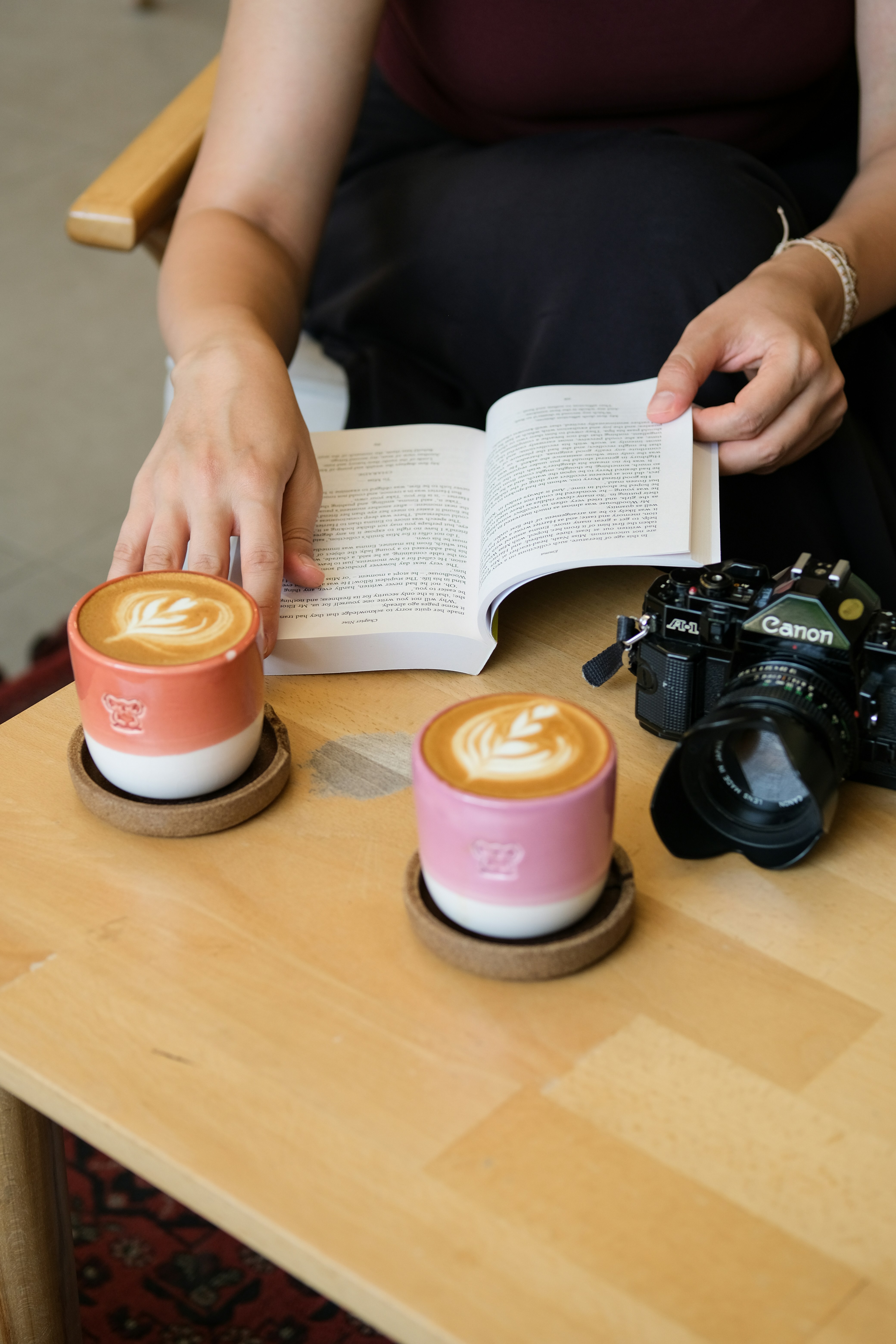 A Quiet Café Moment: Hands, Book, and Camera by Latte