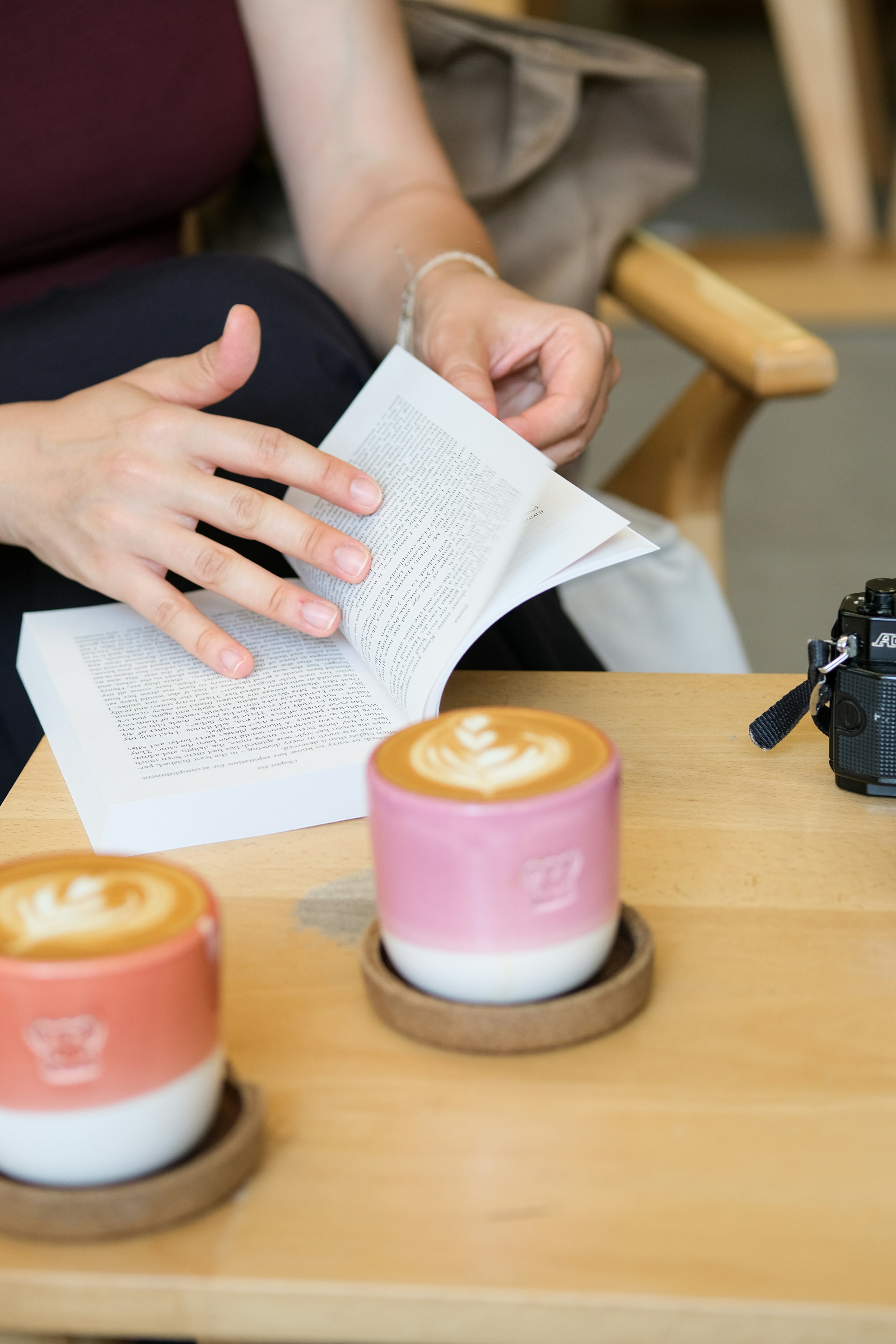 Paused Moment: A Reader's Hands Hover Over Text Among Latte Hearts