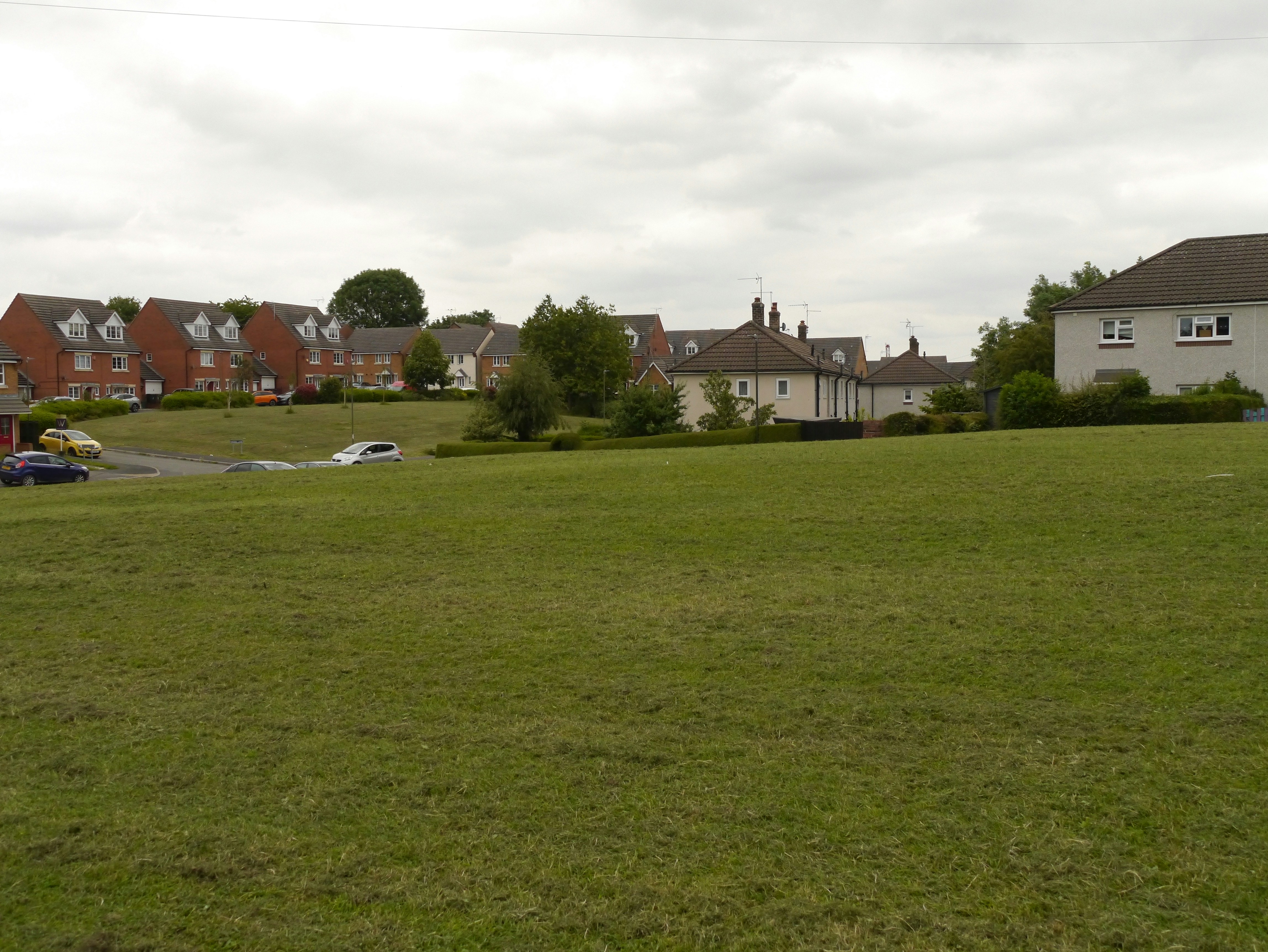 Quiet suburban field with distant row of houses under a cloudy sky
