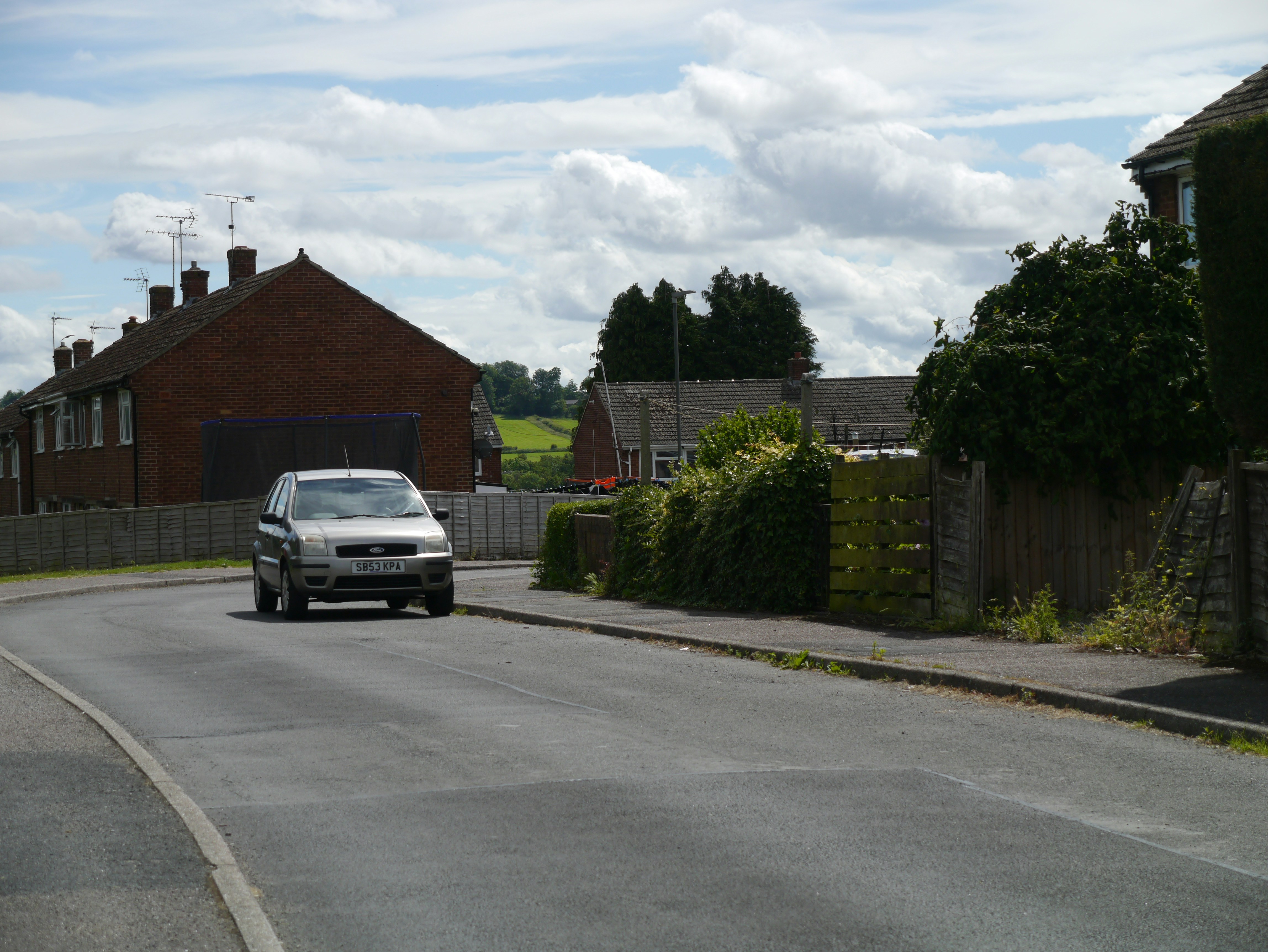Compact silver car approaching a quiet village street