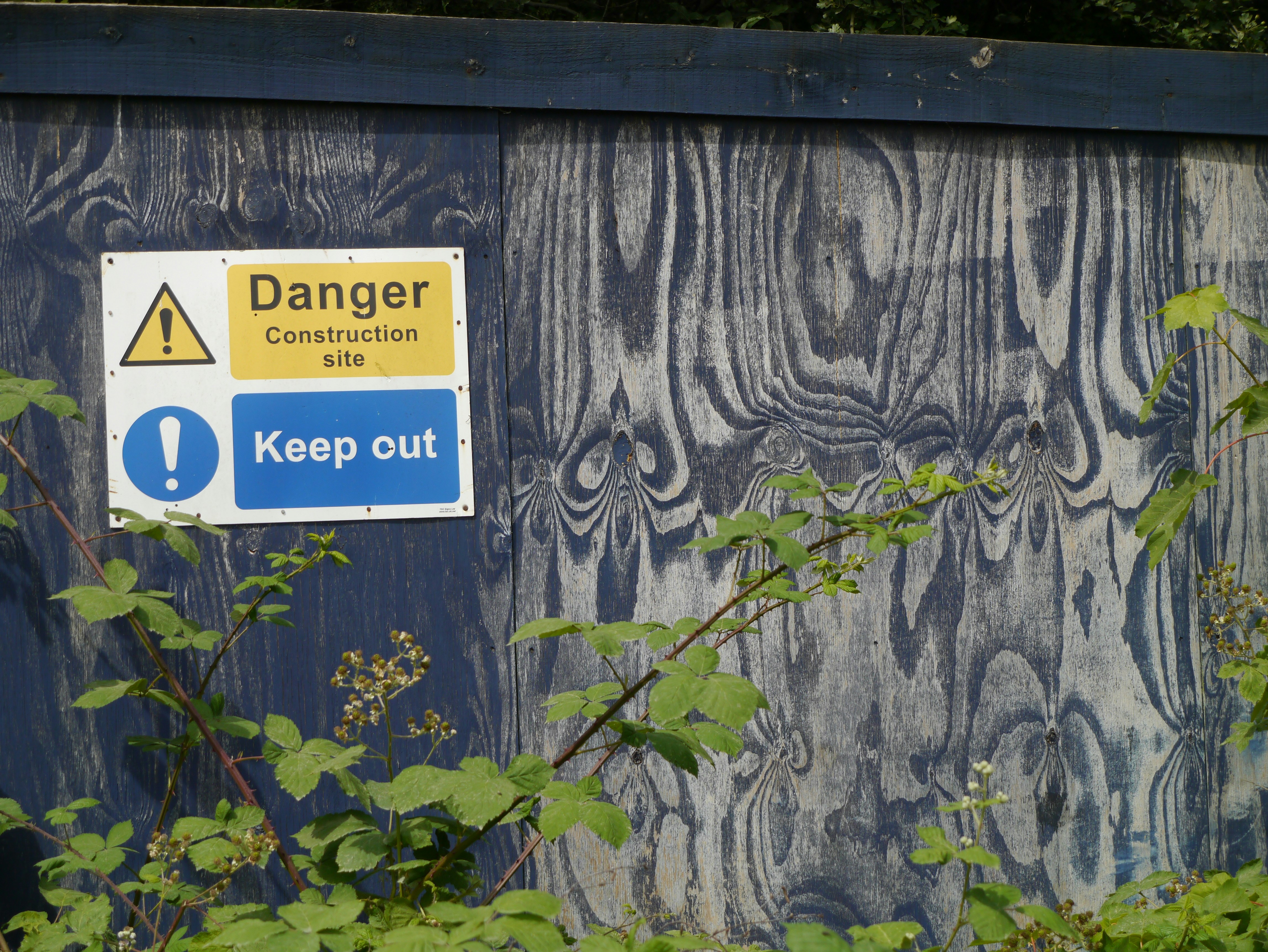 Warning Sign Amidst Weathered Wood and Vines