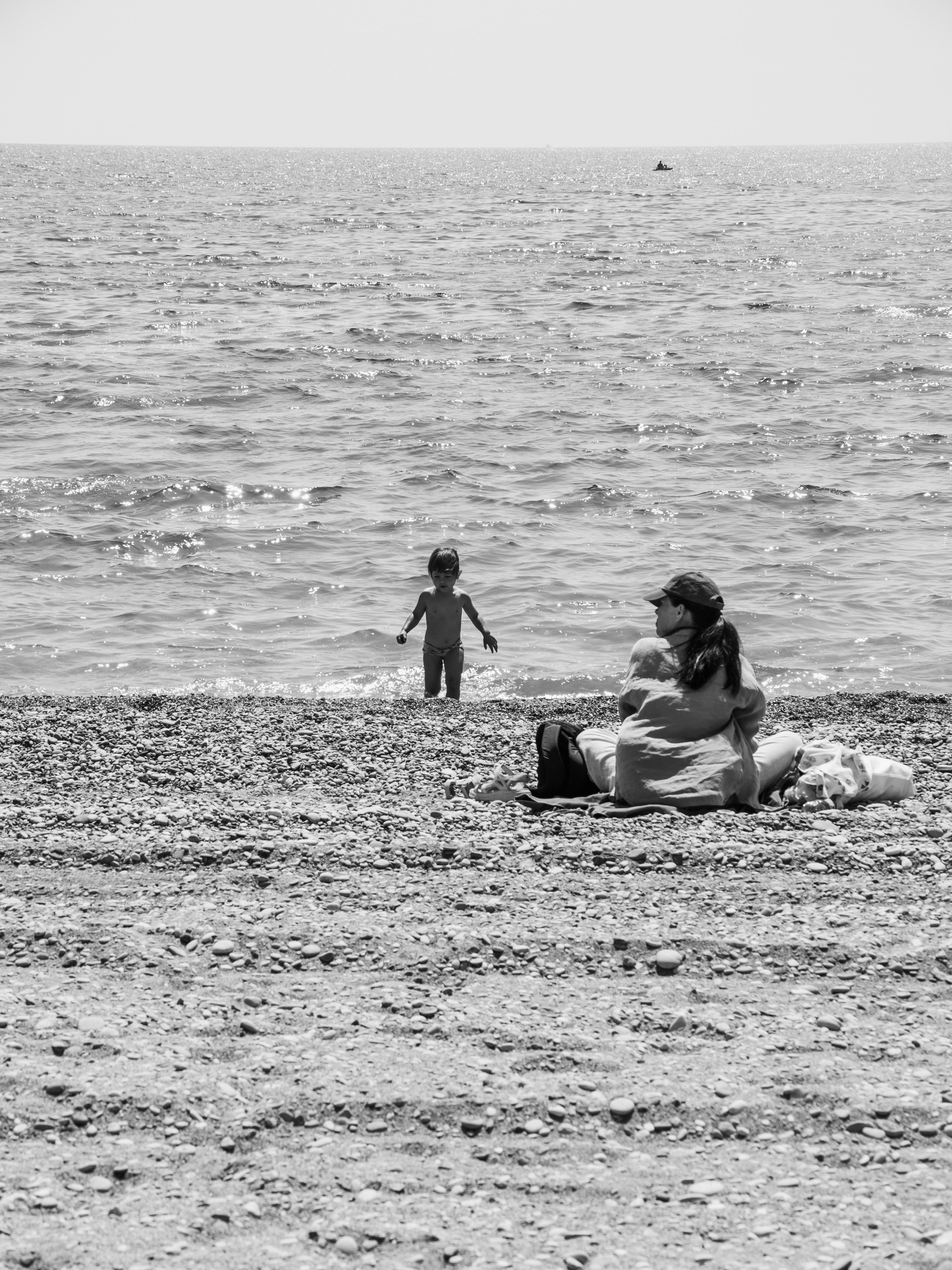 Beachside Pause: A Child Reaches Toward the Sea as a Caregiver Watches