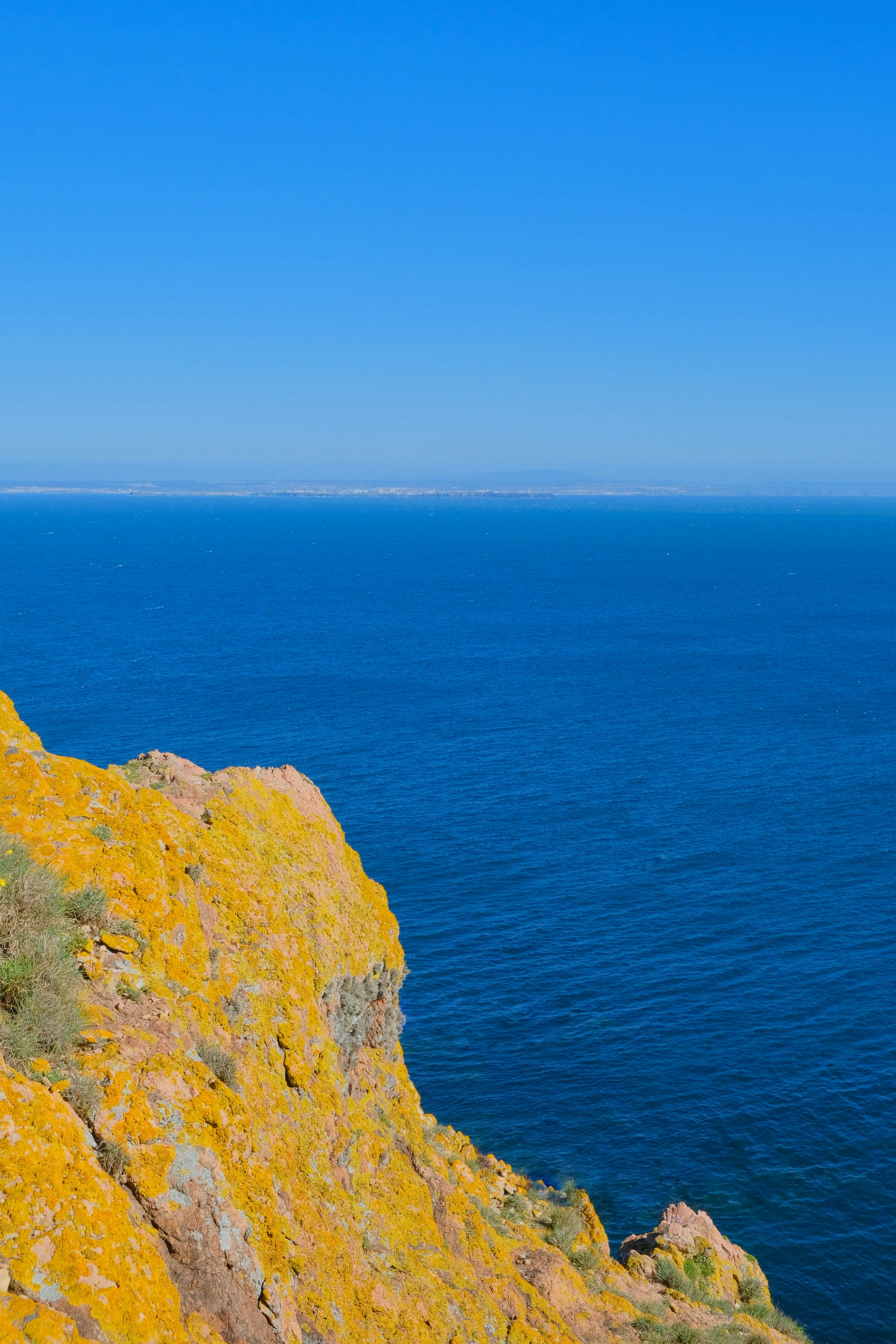 Sunlit Cliff Edge Over Blue Expanse