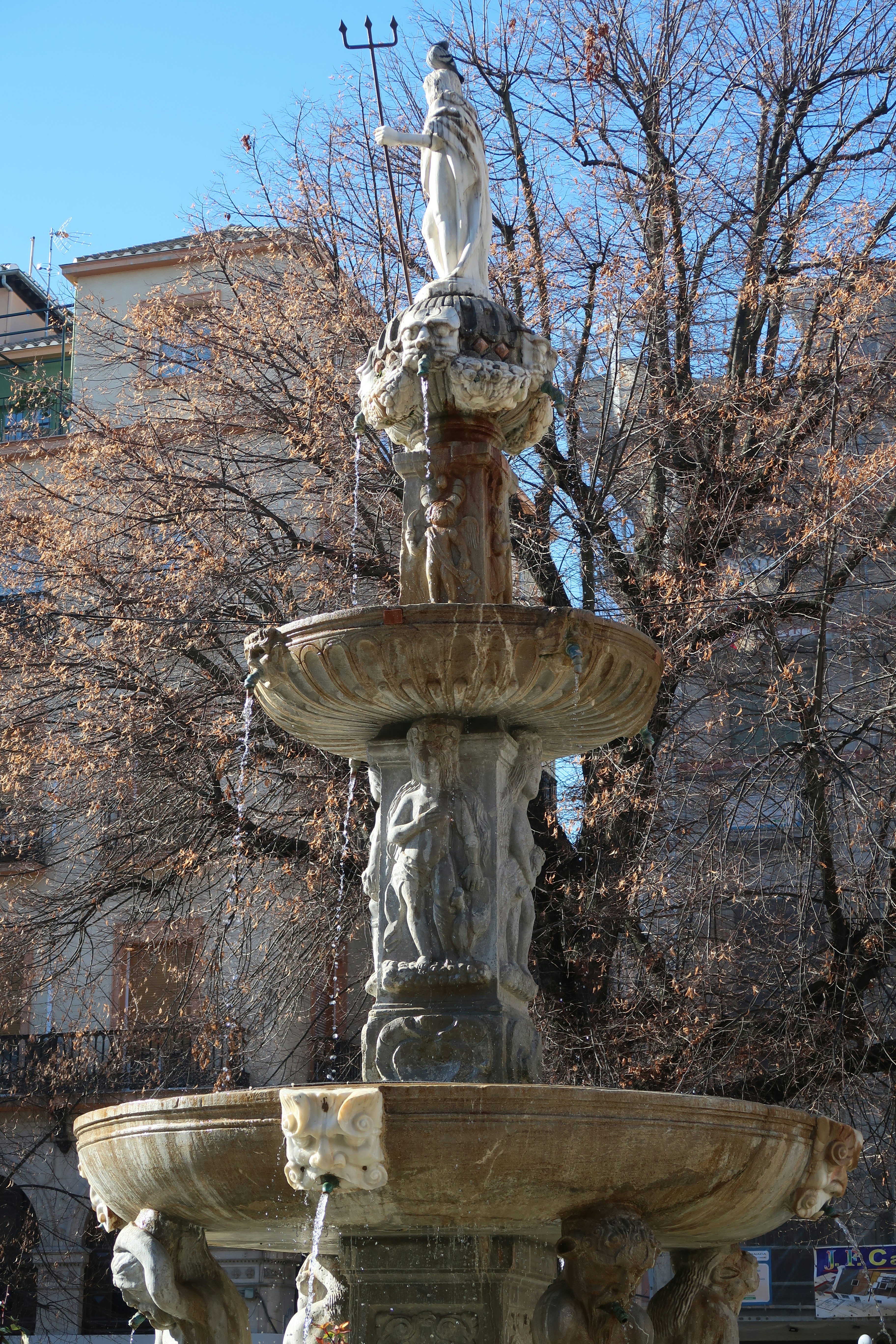 Central fountain statue reaches toward a clear blue sky