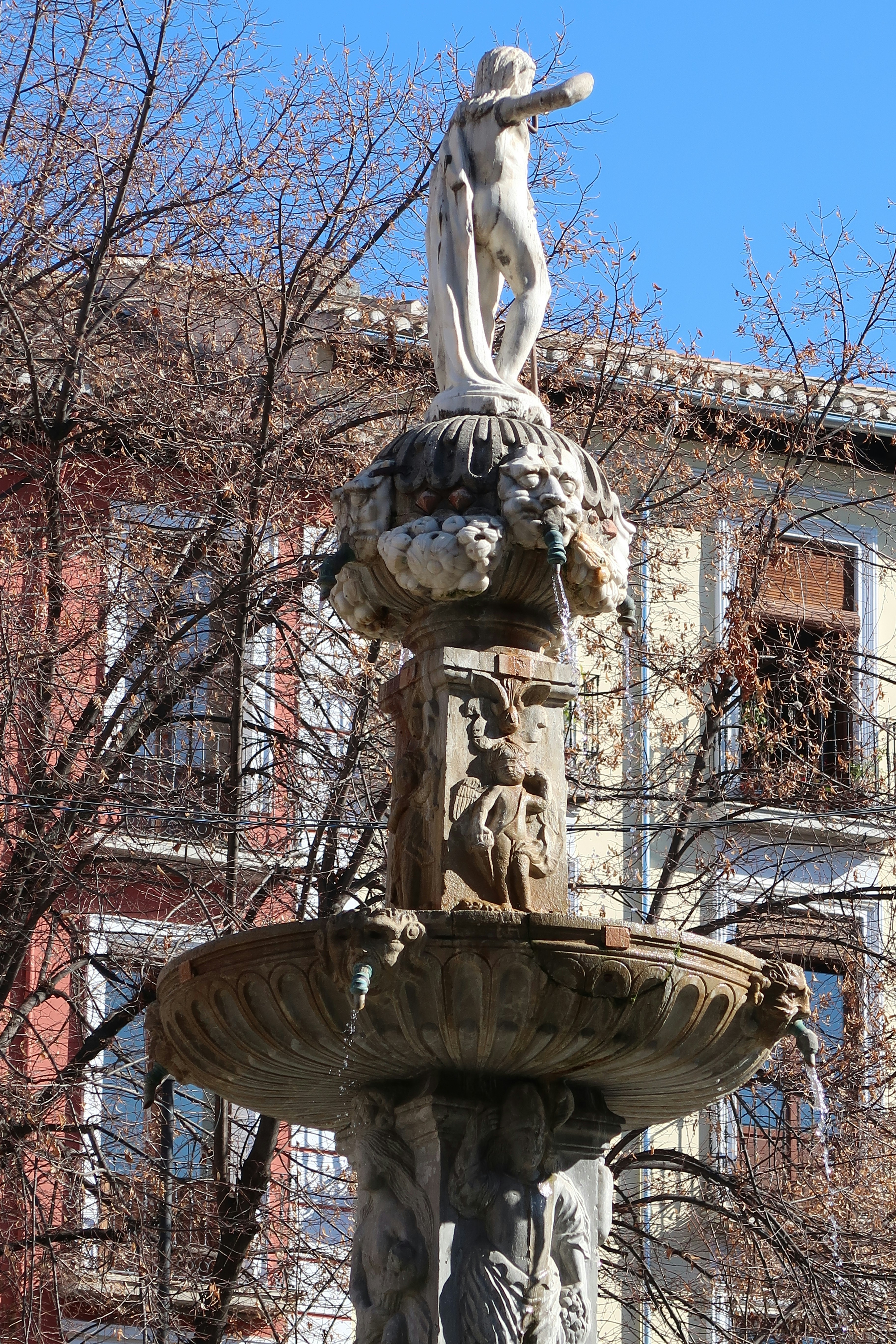 Fountain’s Gilded Embrace: Stone Carvings Under Blue Sky