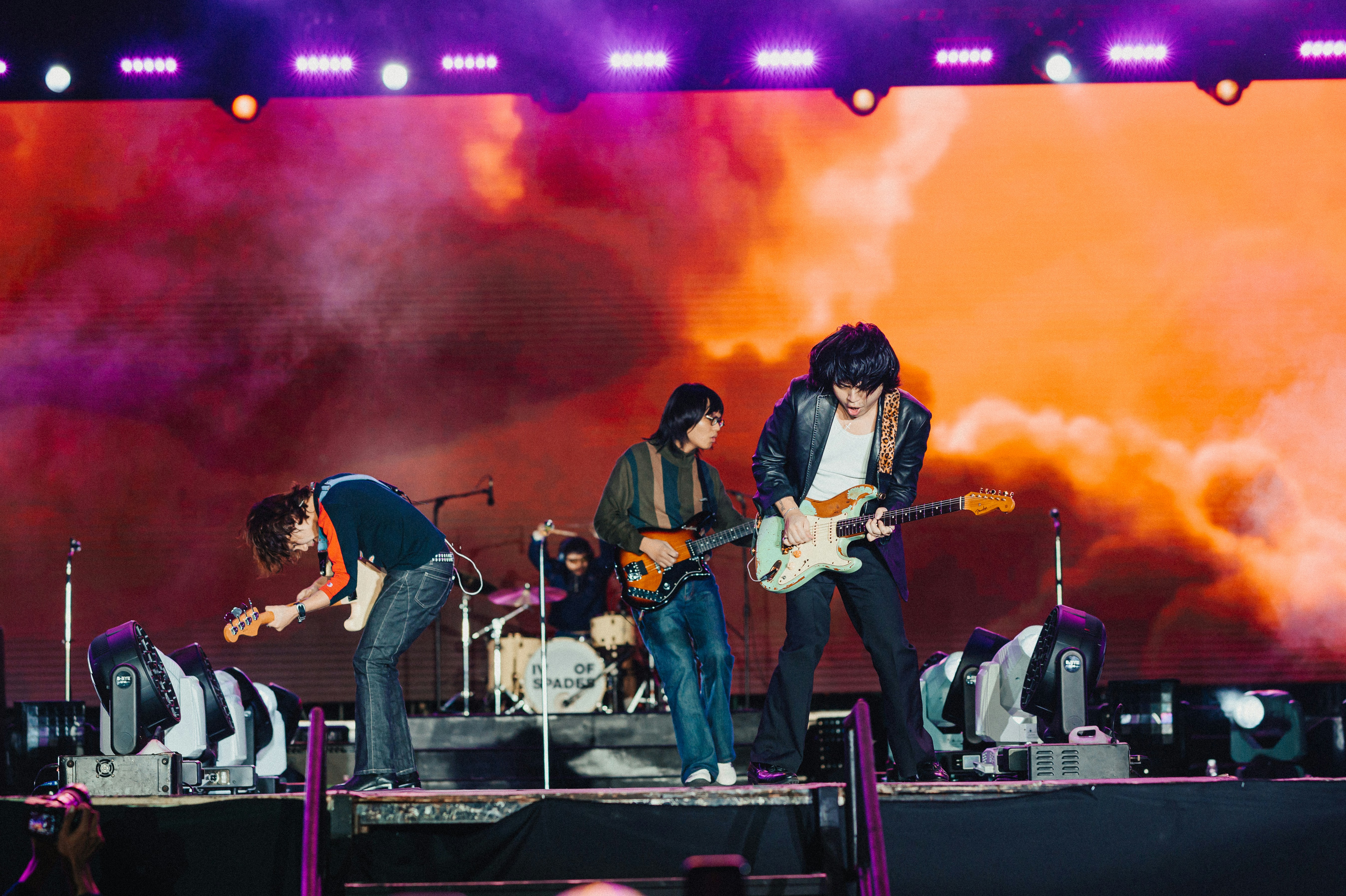 Electric Confluence: A Band Ignites a Stage Under Fiery Backdrop