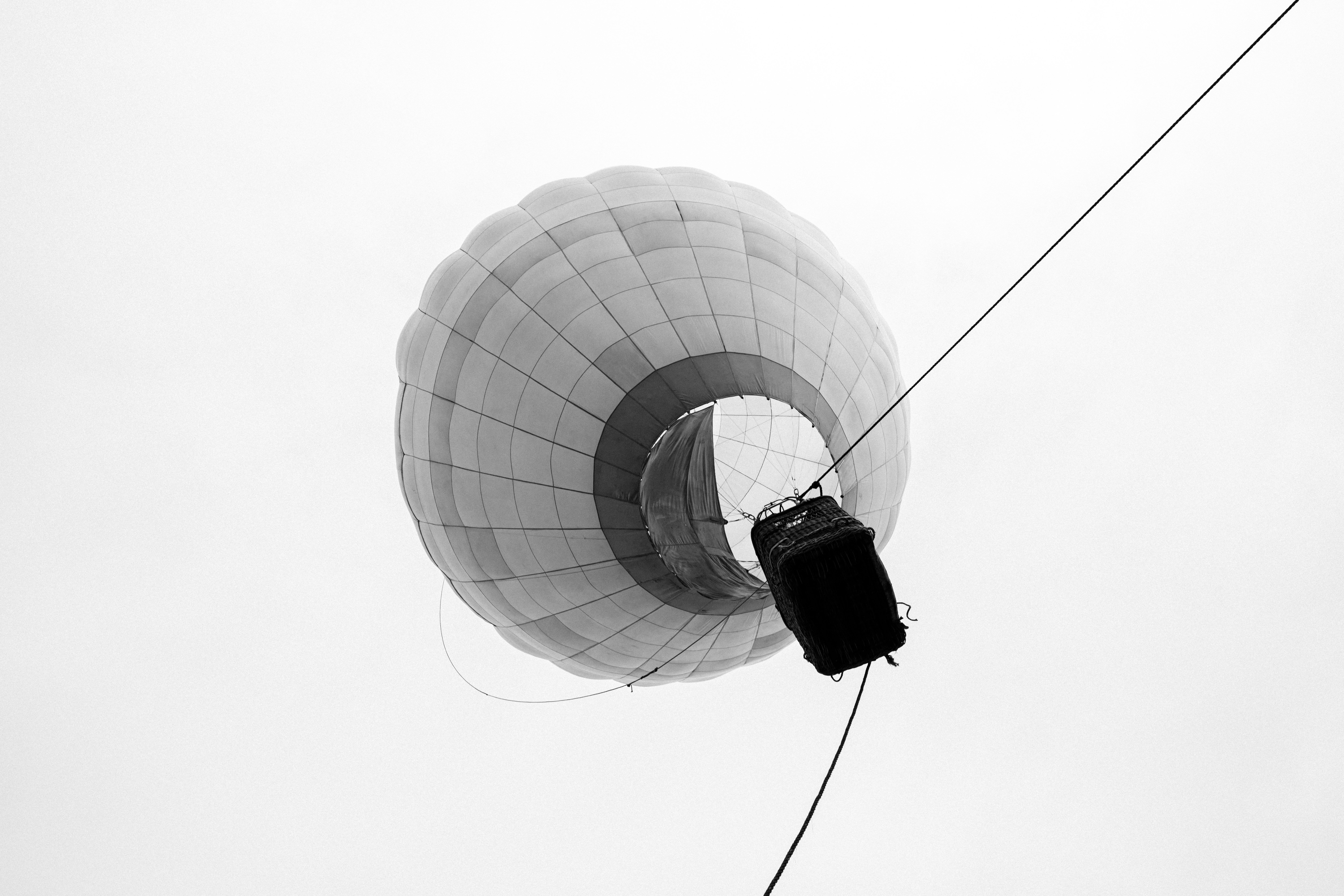 Airborne Lantern: Helium Balloon and Cables against a Pale Sky
