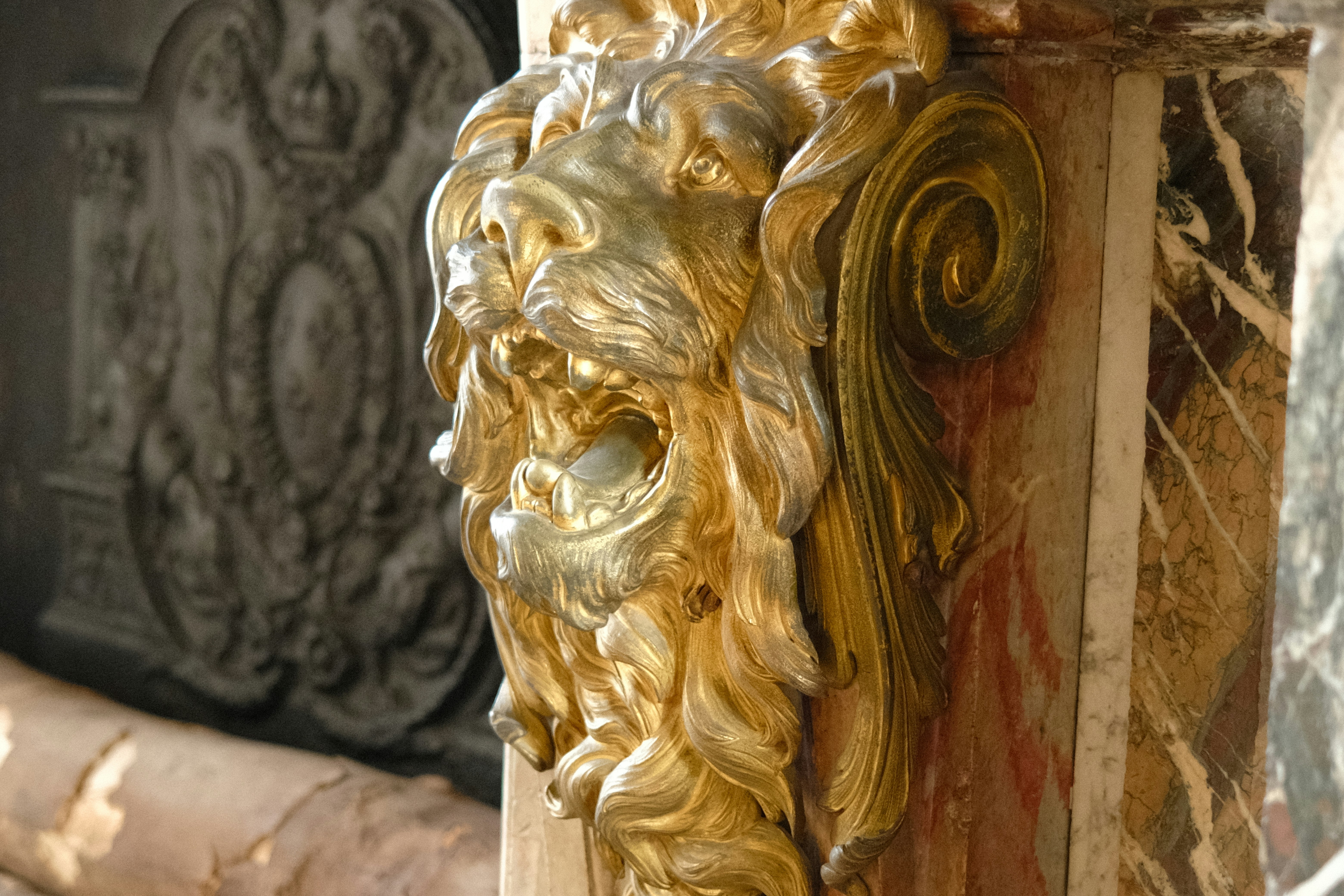 Gilded lion’s head detail anchoring a marble column