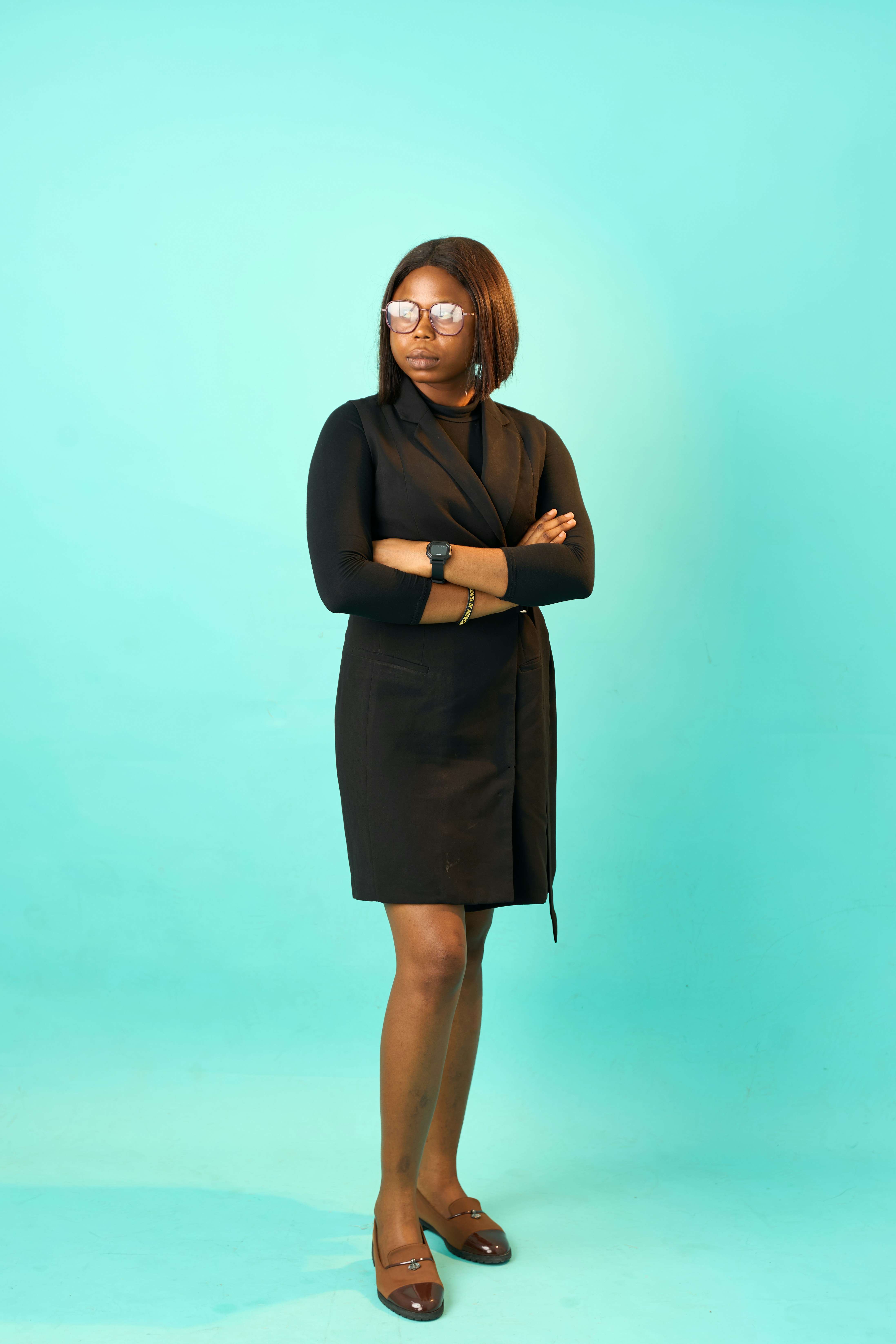 Confident stance in a mint studio: a poised professional in a black wrap dress
