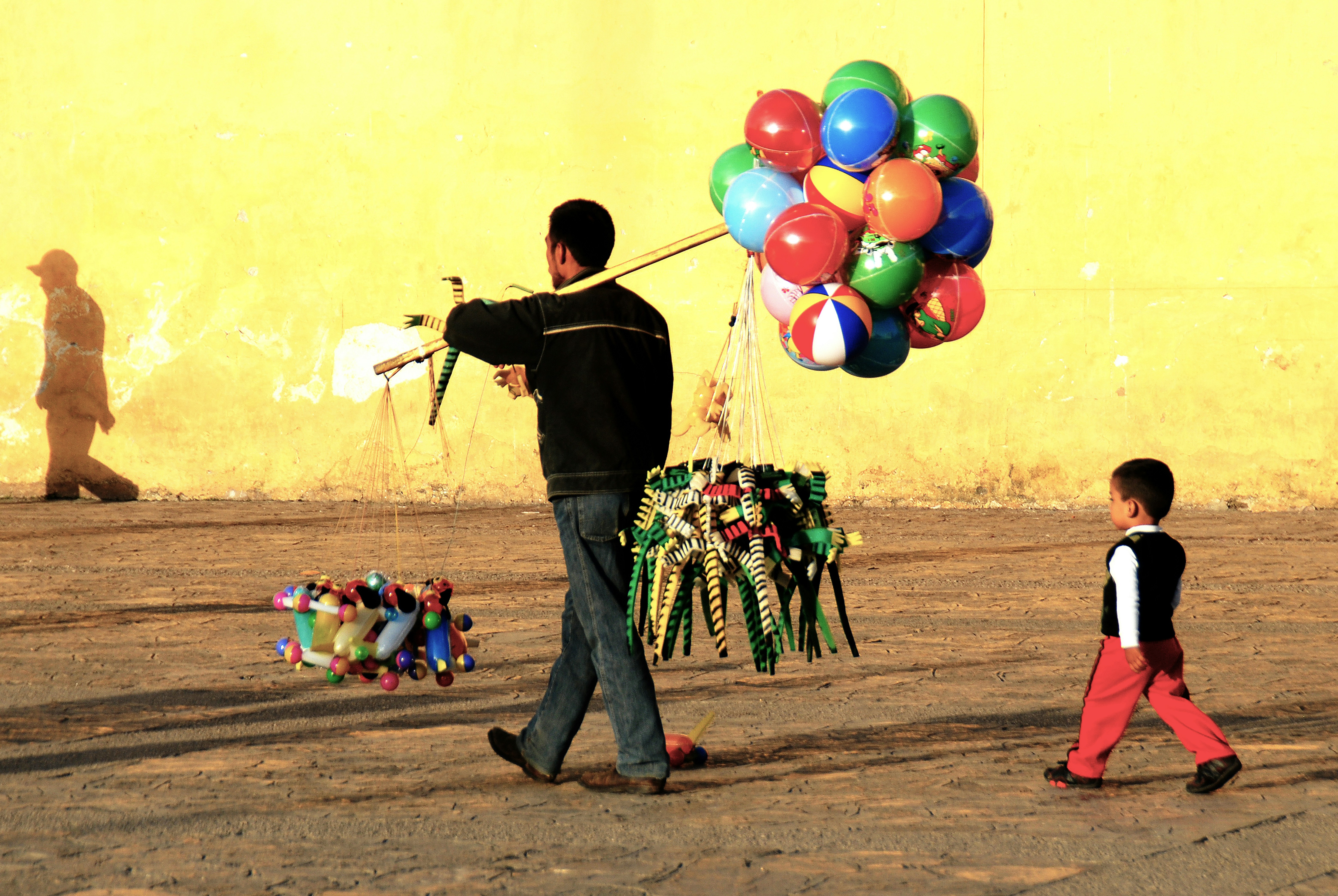 Balloon-laden vendor and boy in a sunlit square