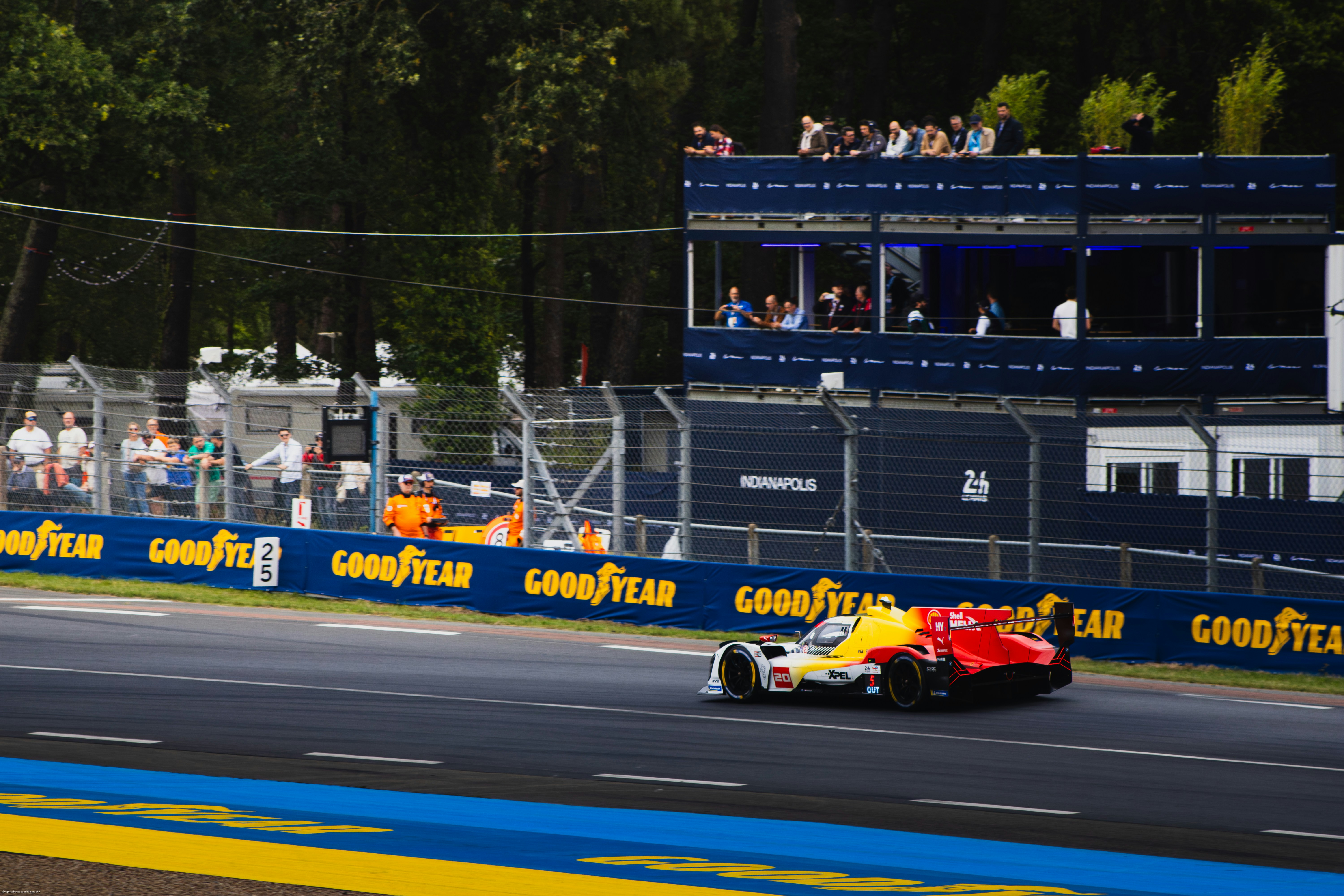 Red Formula car in mid-race blur beside blue pit building