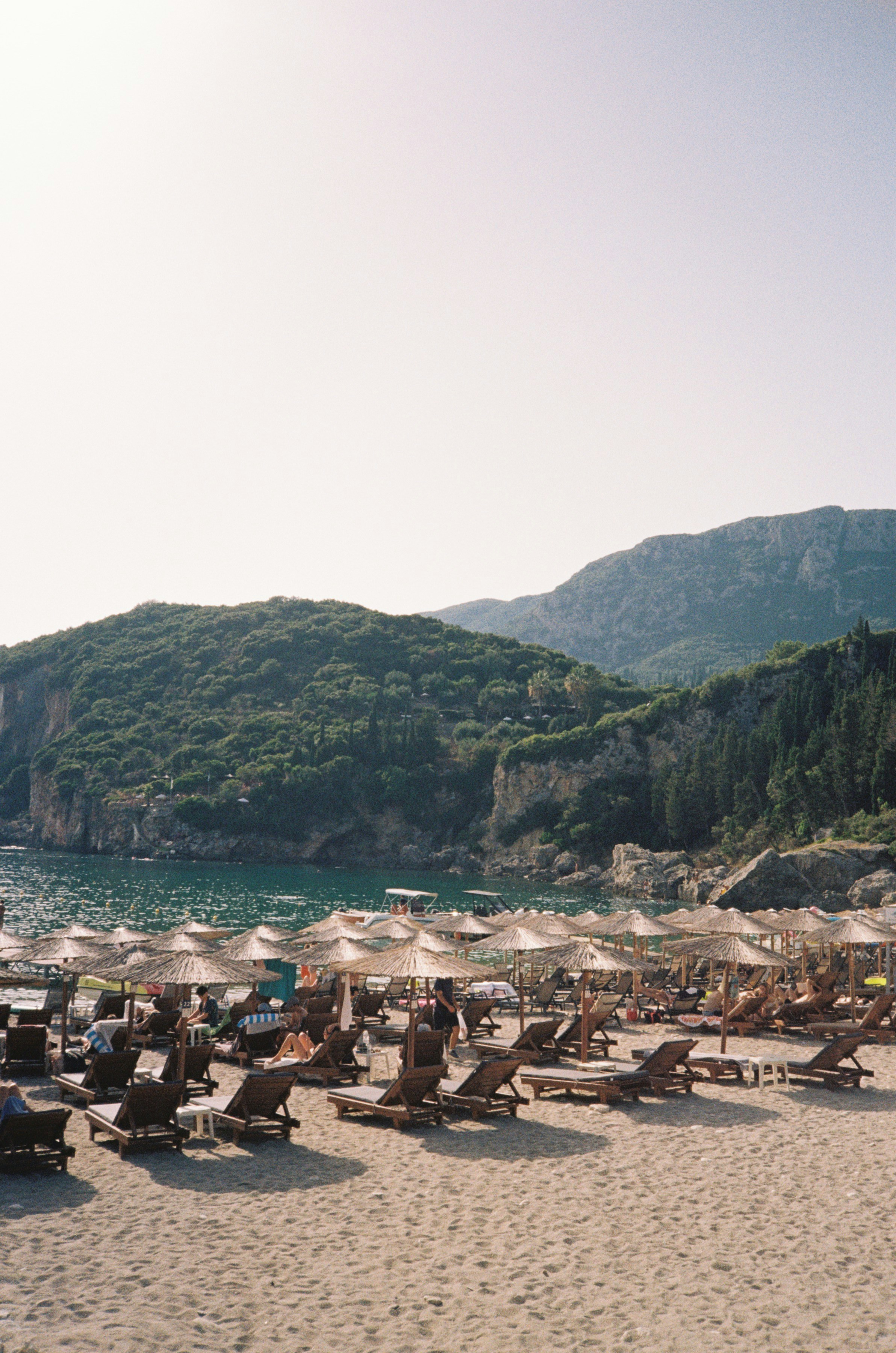 Sunlit Cove with Beach Chairs and Distant Peaks