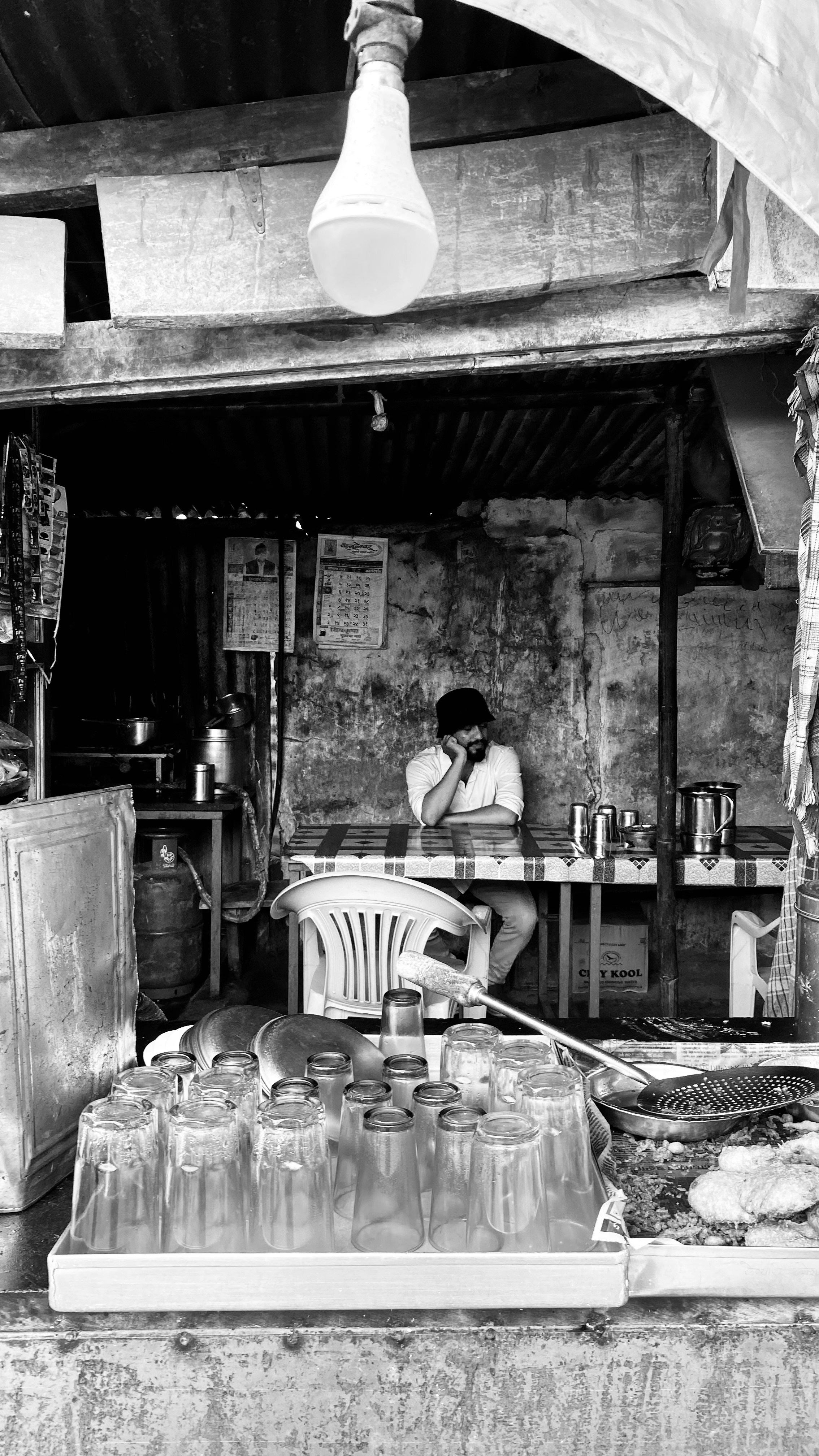 Street-side stall in monochrome with a lone vendor at a striped table