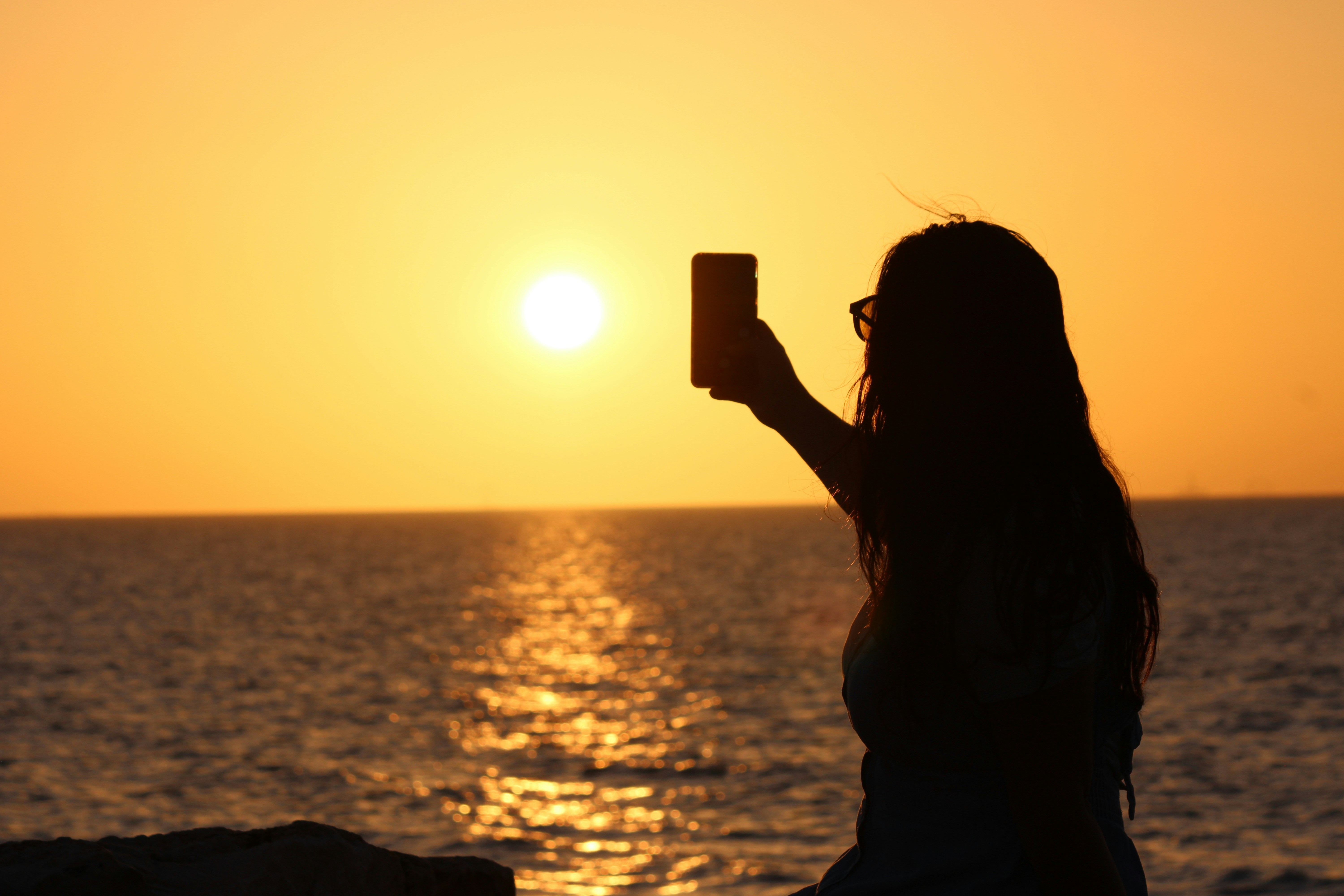 Sunlit Silhouette: A Moment with a Selfie by the Sea