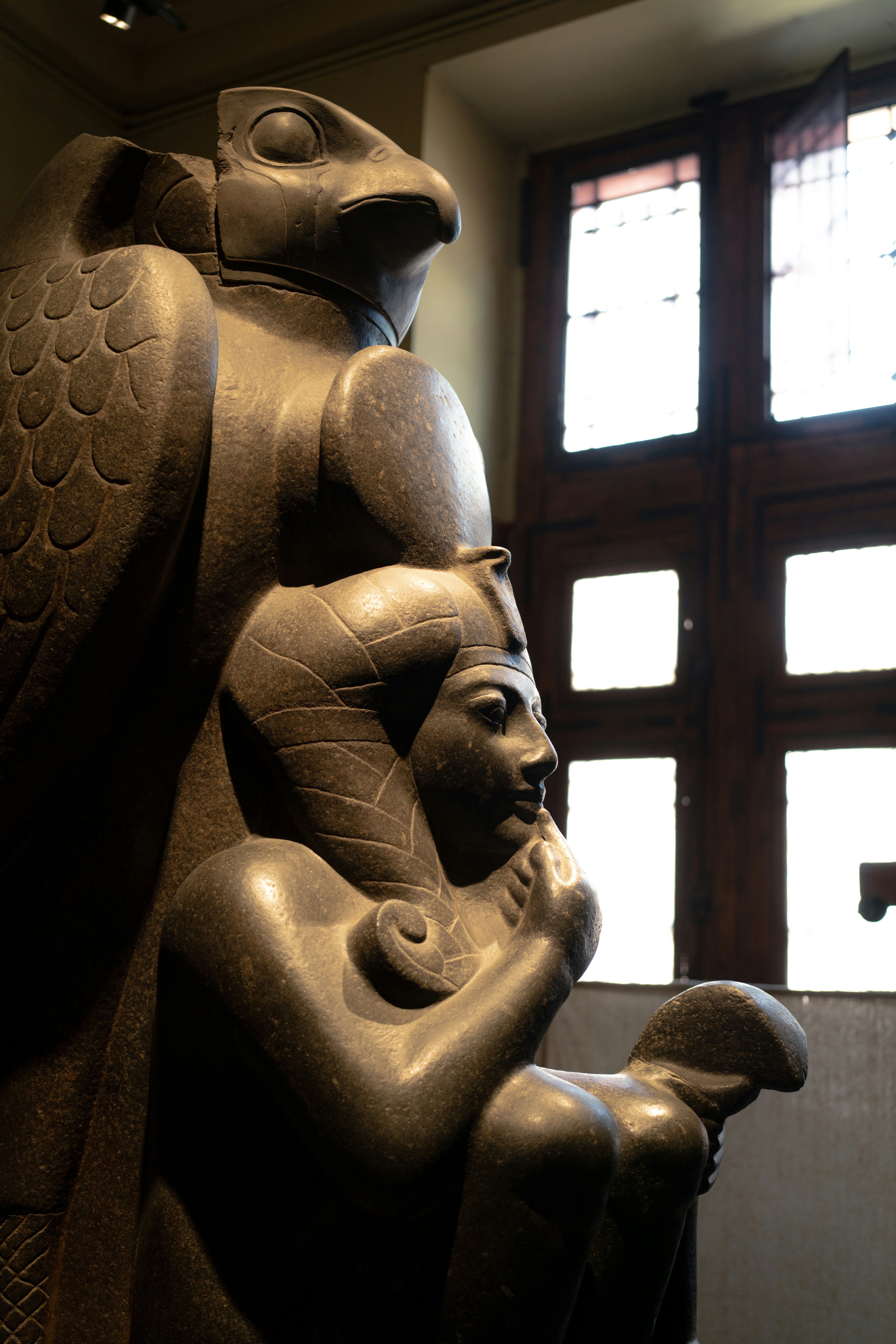 Guarded Gaze: A Stone Sphinx Embracing a Child in Dim Cathedral Light