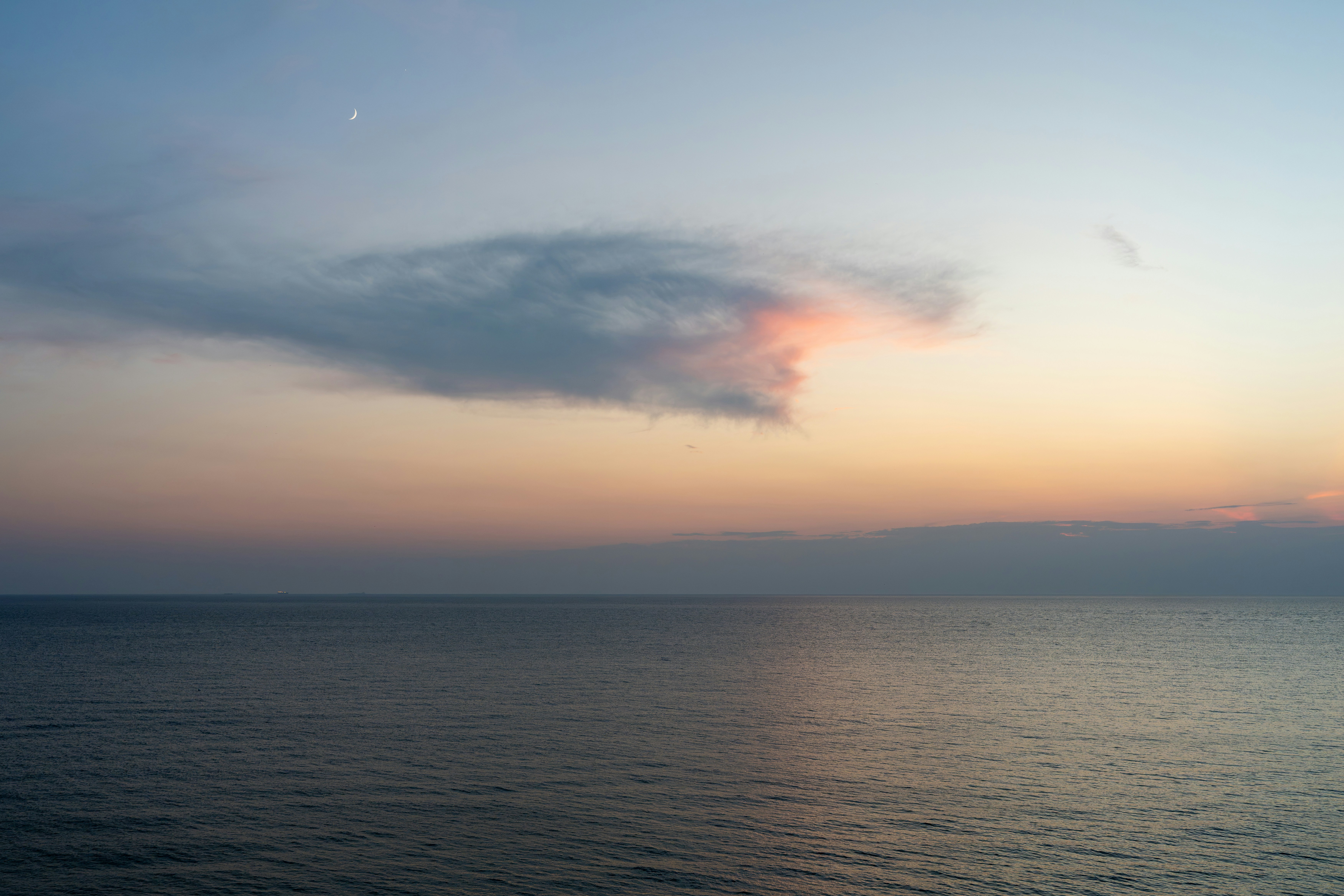 Dawn Over Quiet Waters: Subtle Nebula of Clouds and Crescent Moon