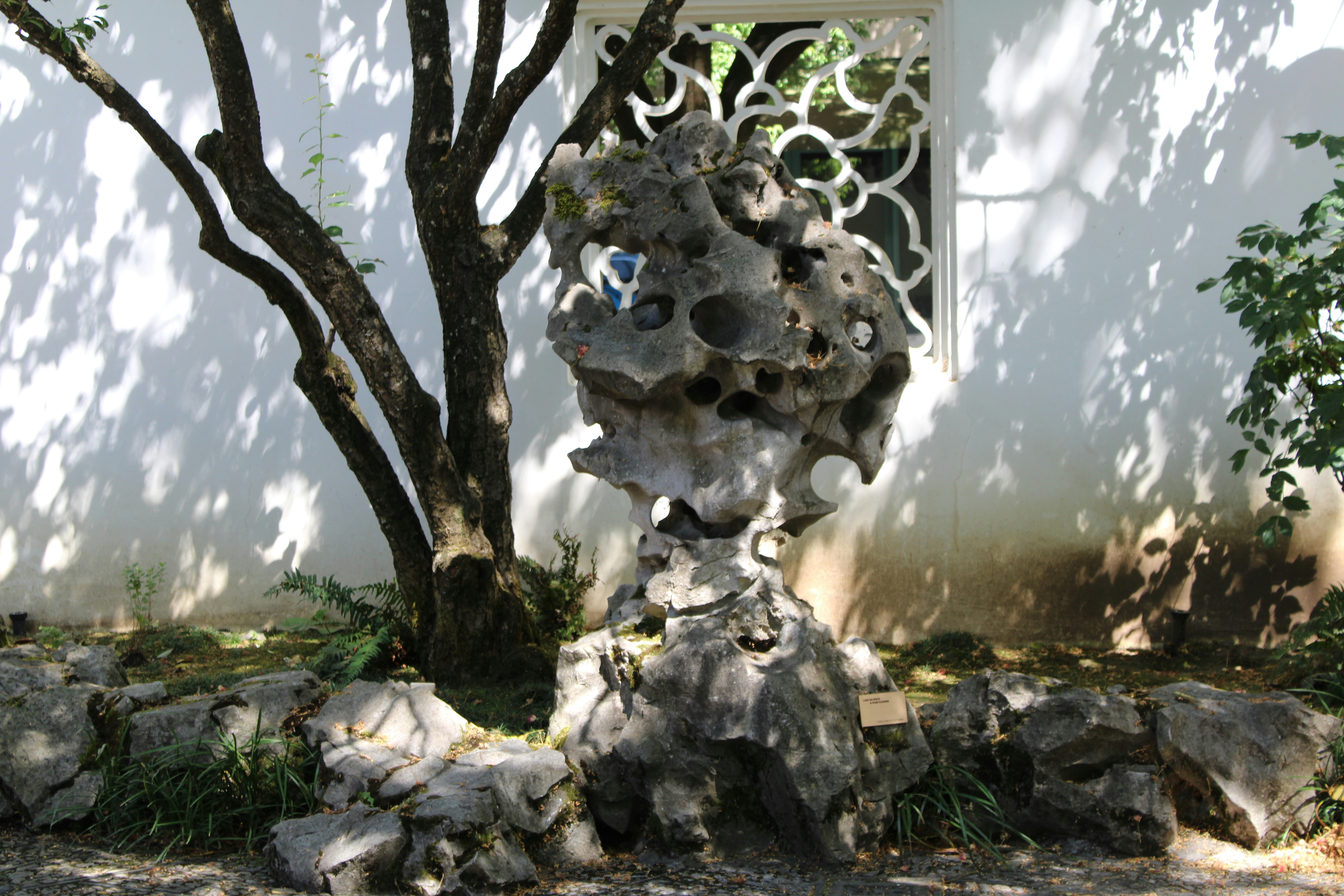 Stone sculpture amid dappled shade in a sunlit courtyard