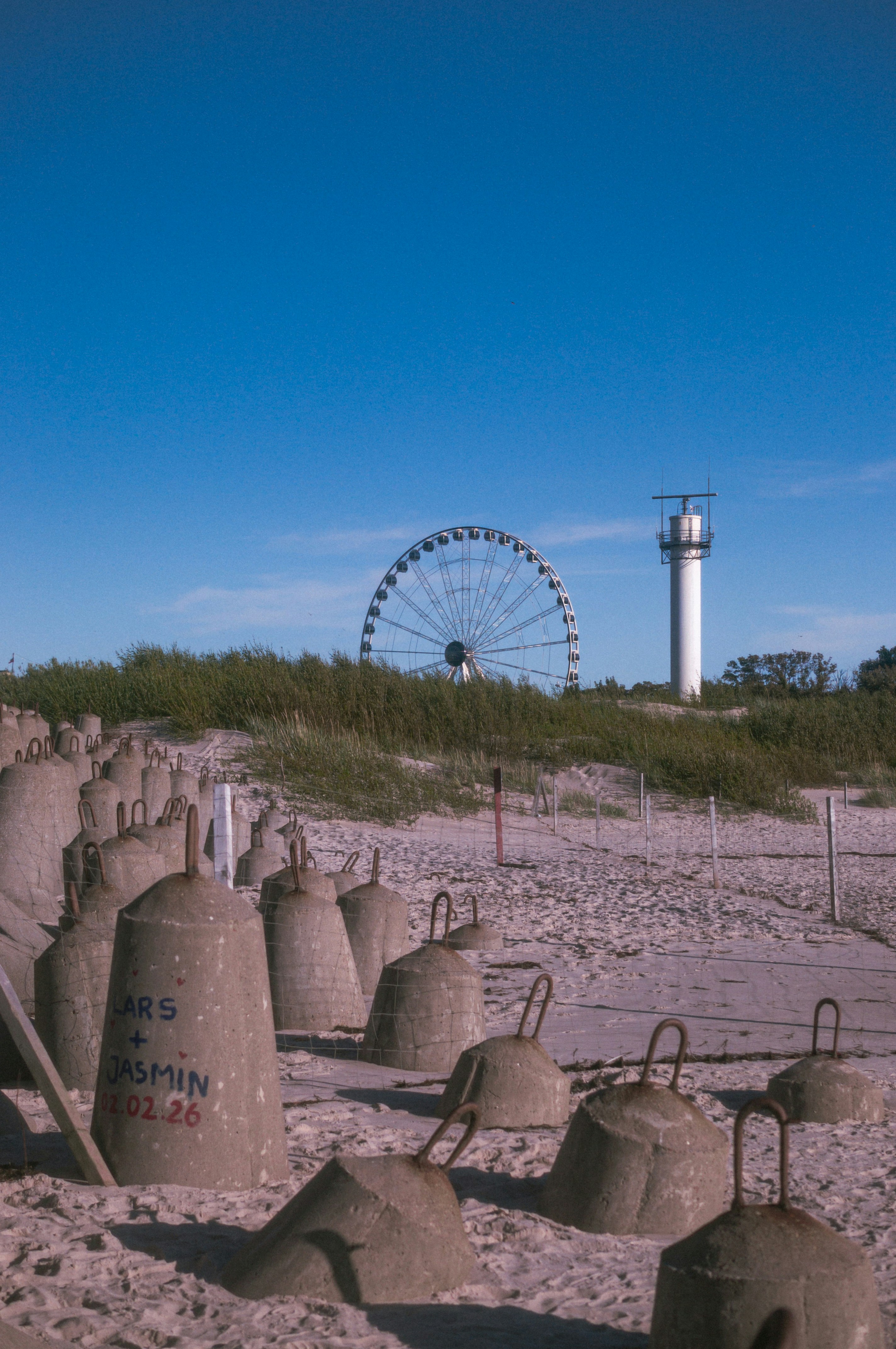 Coastal Playground: Ferris Wheel and Lighthouse Against a Quiet Dune Field