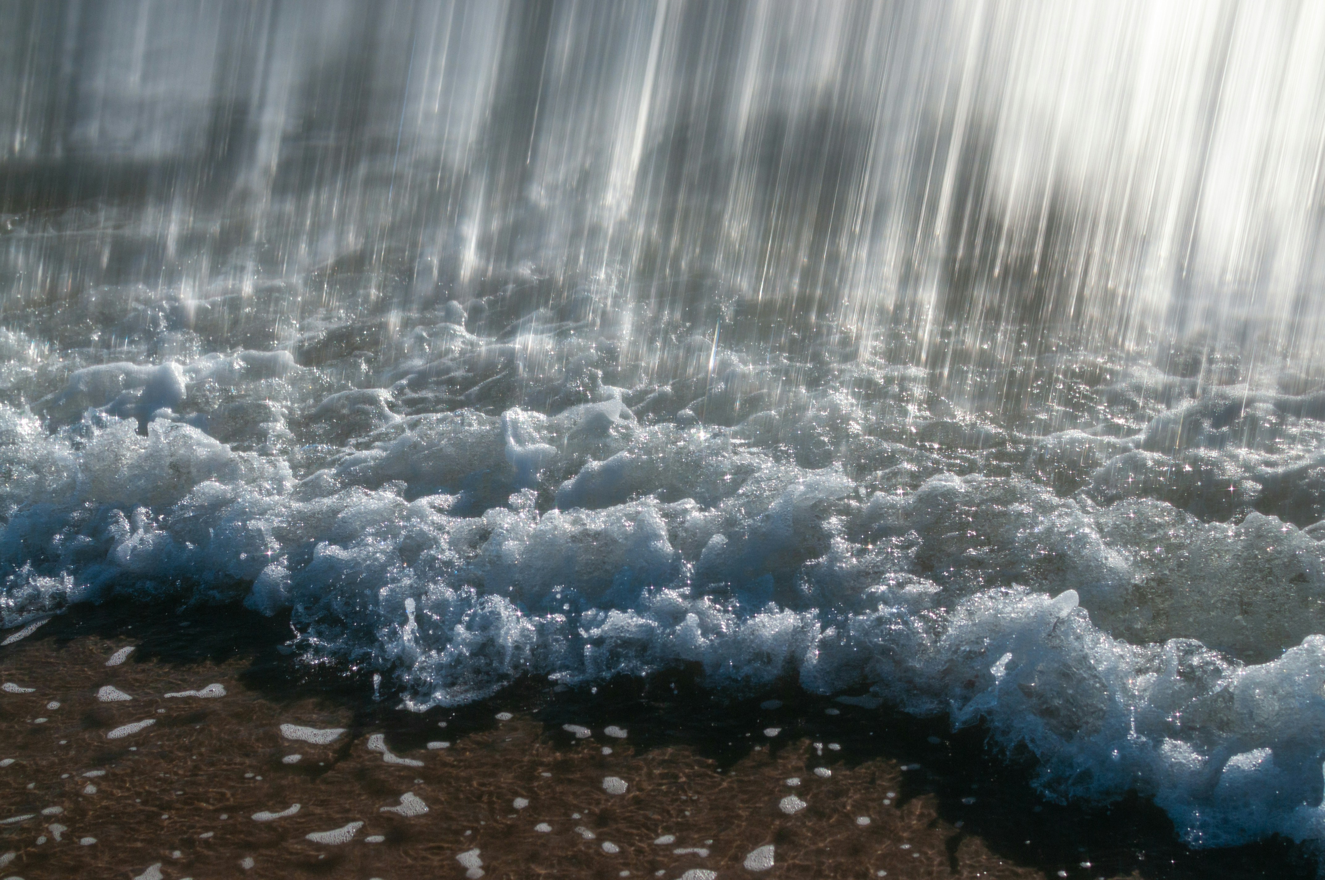 Foamy shoreline in a curtain of rain-driven spray