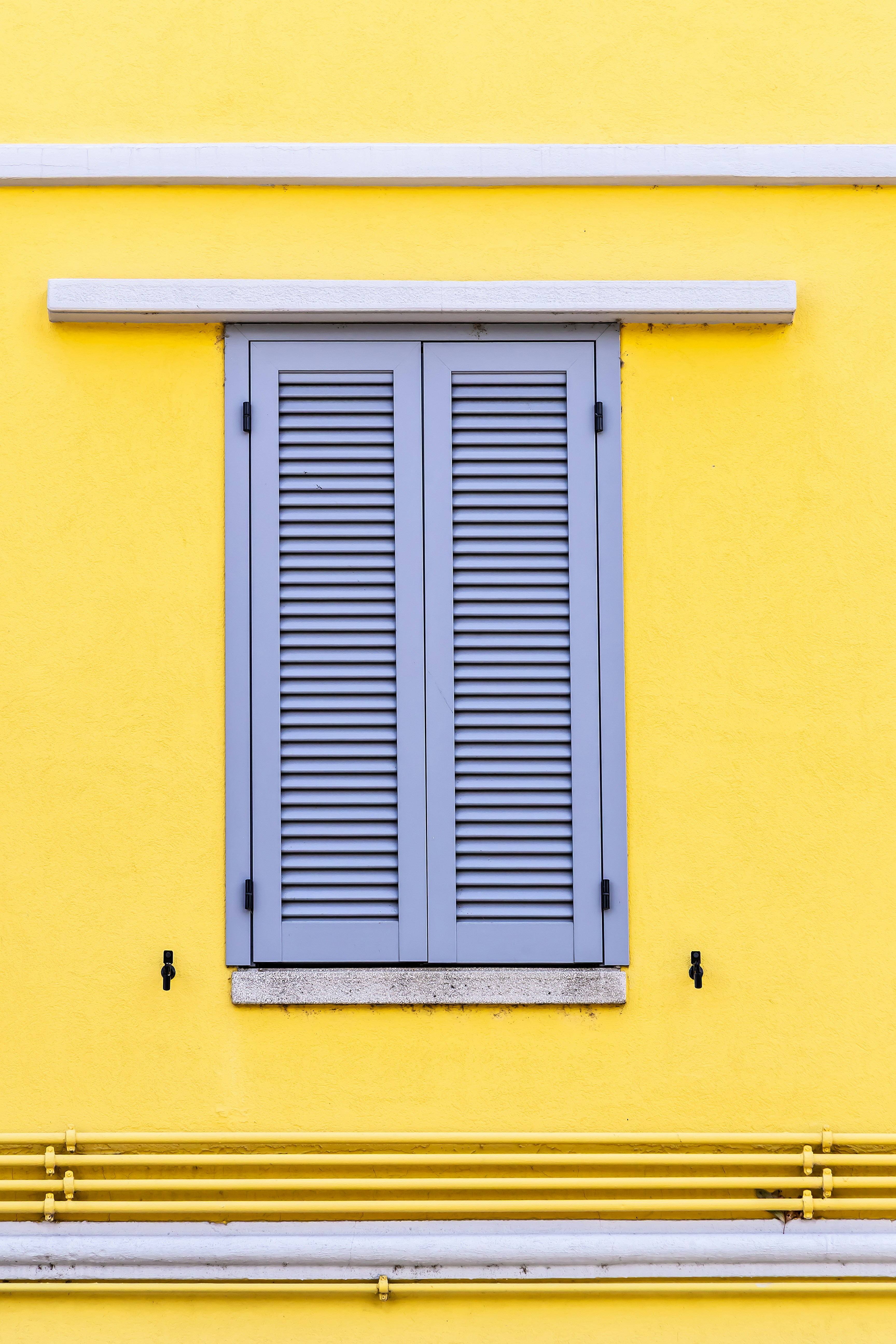 Blue Shutter Windows on a Sunlit Yellow Facade