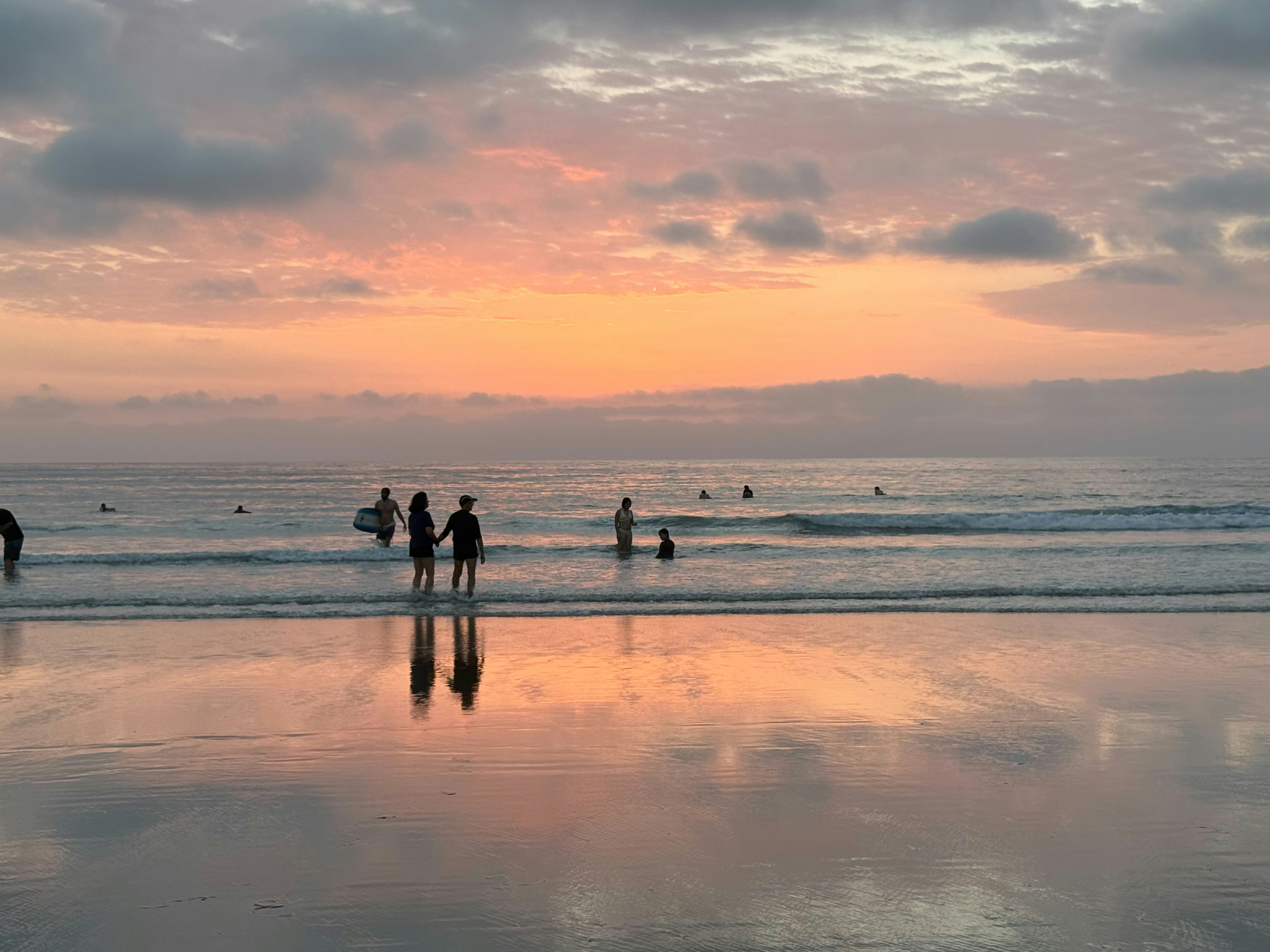 Silhouetted Beachgoers at Sunset Reflecting on Tidal Wet Sand