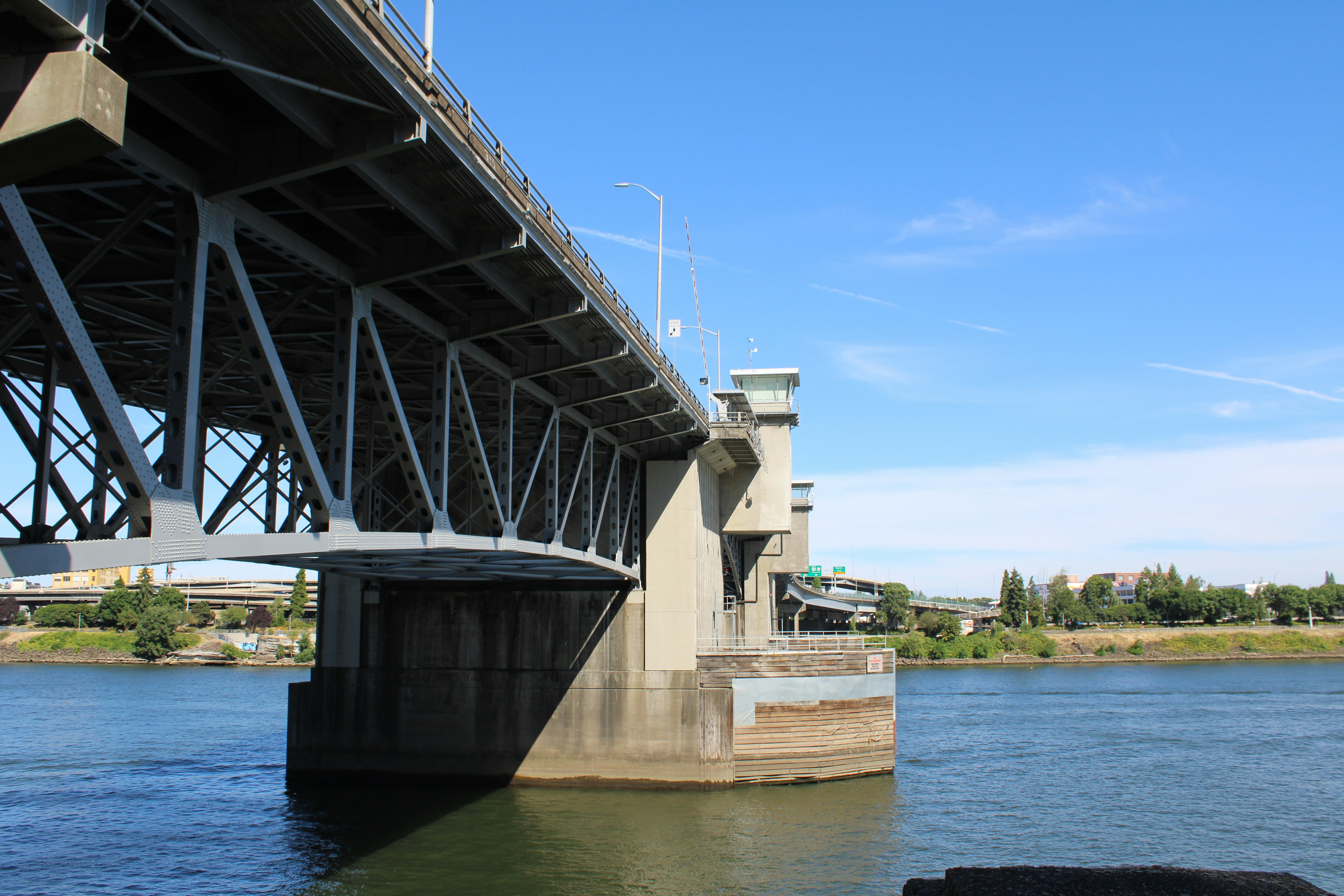 Under the Span: A Quiet Riverside Bridge Slices the Sky
