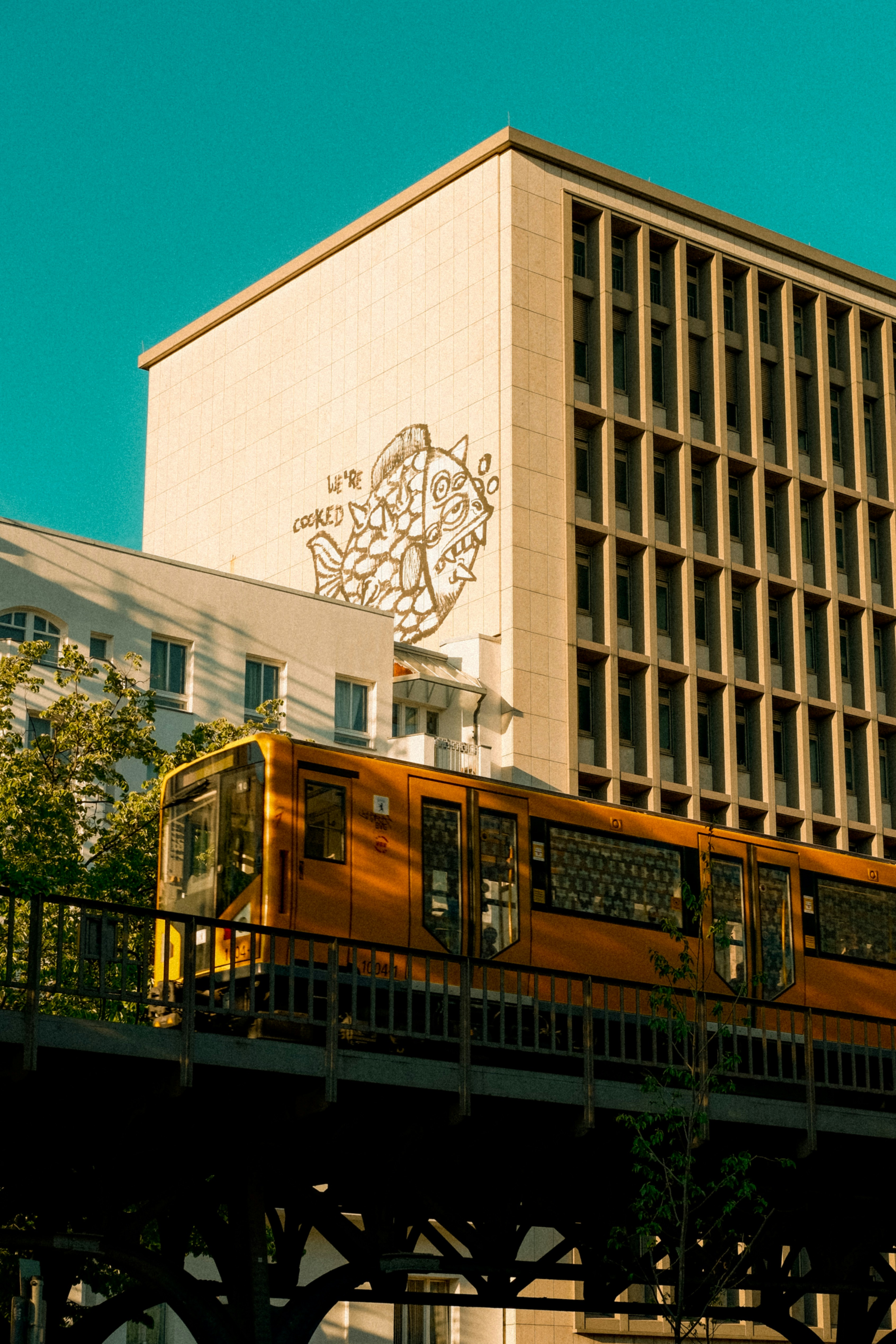 Golden Train, Concrete Facade: A City Scene Under Teal Sky