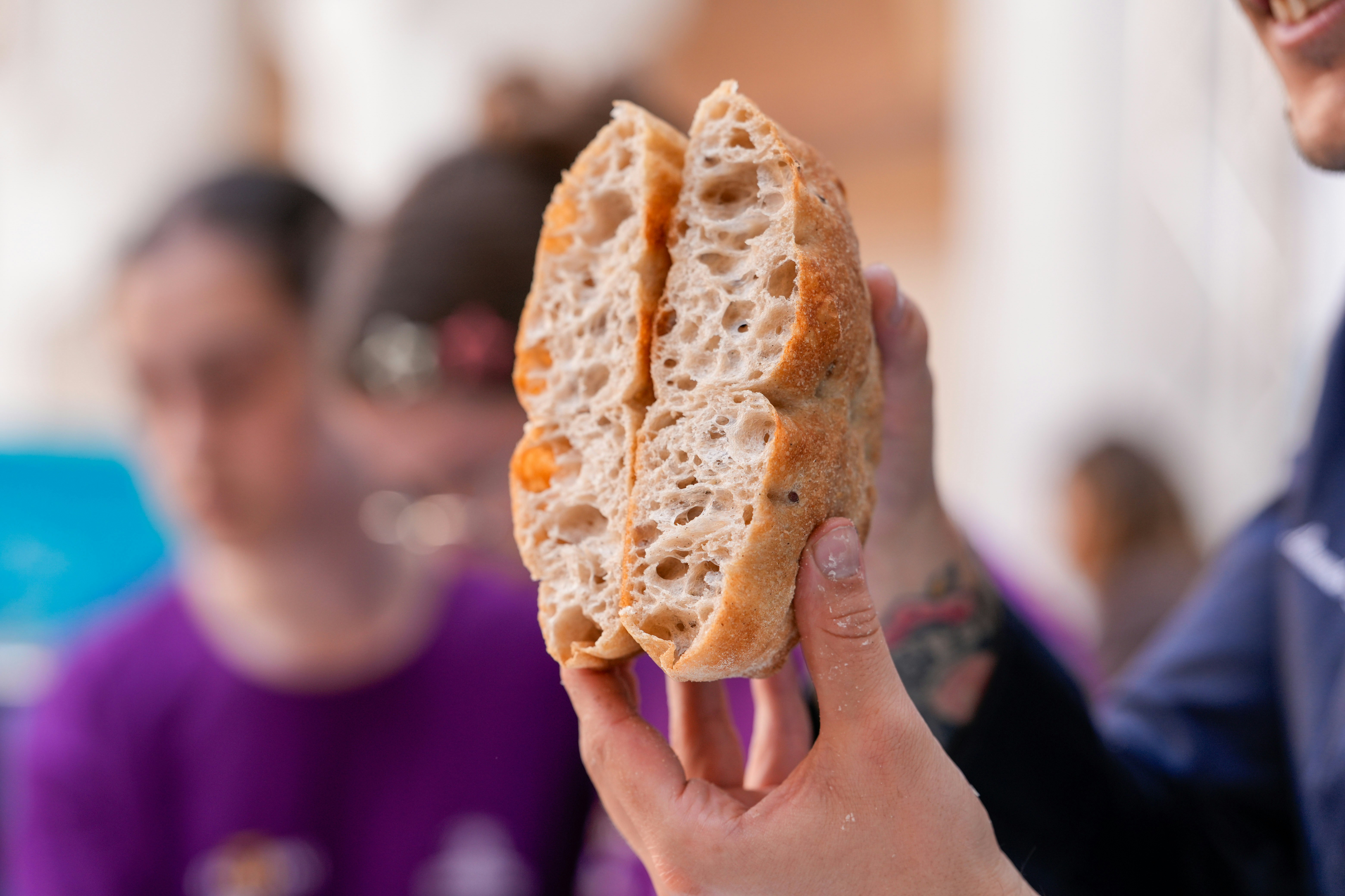 Crusty Handheld Focus: A Slice of Artisan Bread in a Busy Kitchen