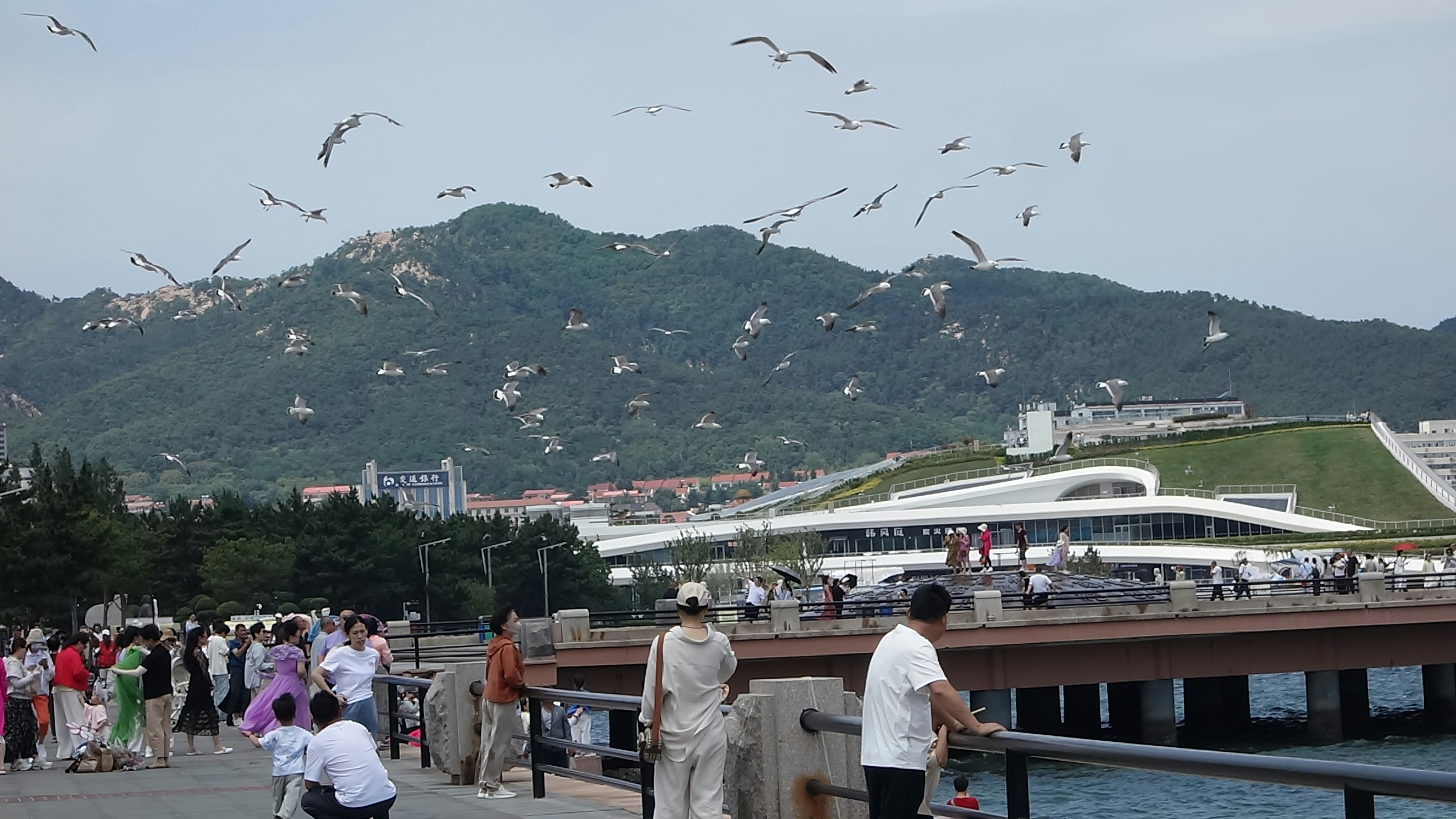 Riverside promenade beneath a modern pavilion as crowds gather