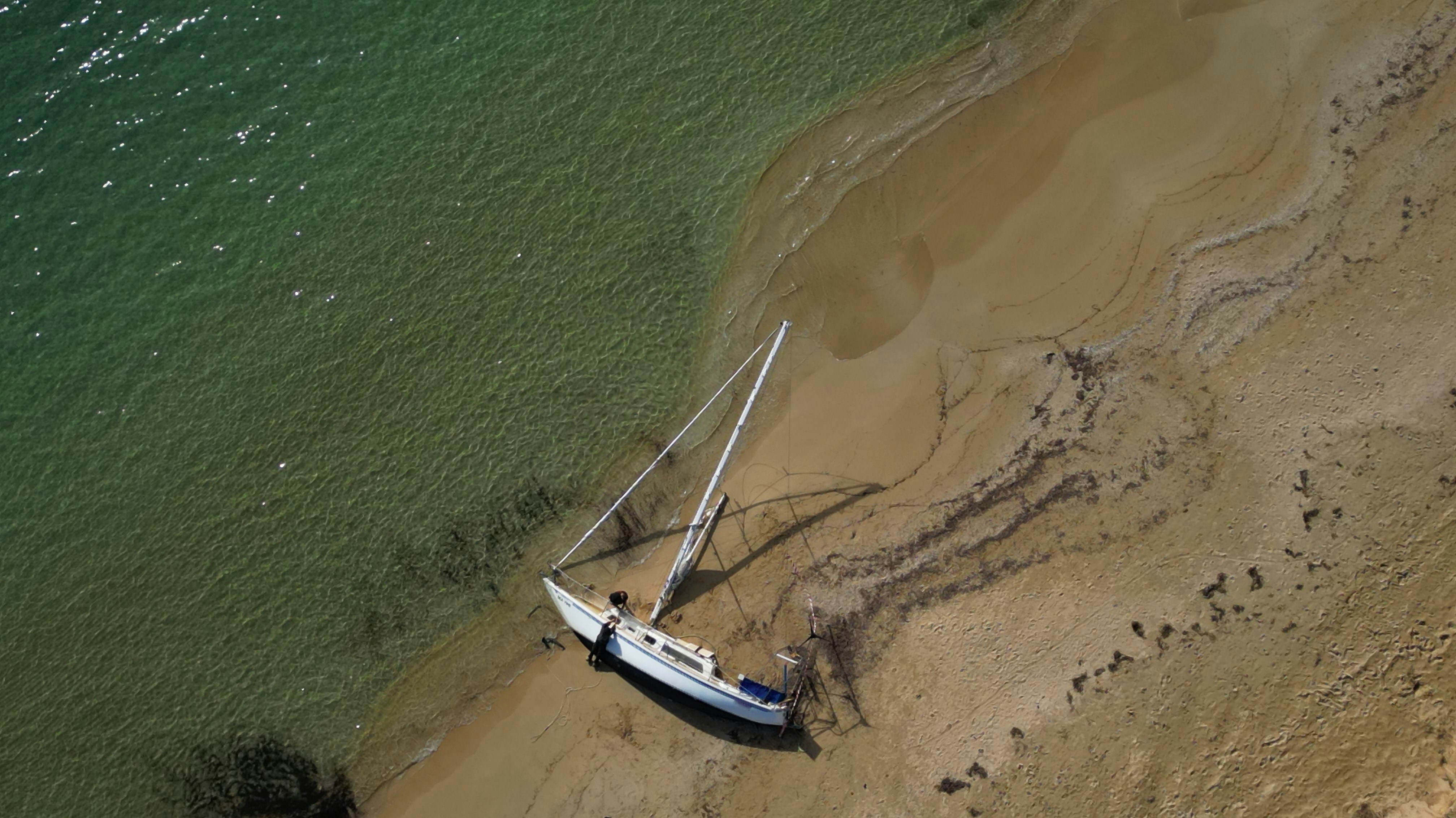 Sailboat Resting on a Muddy Shoreline from Aerial Drift