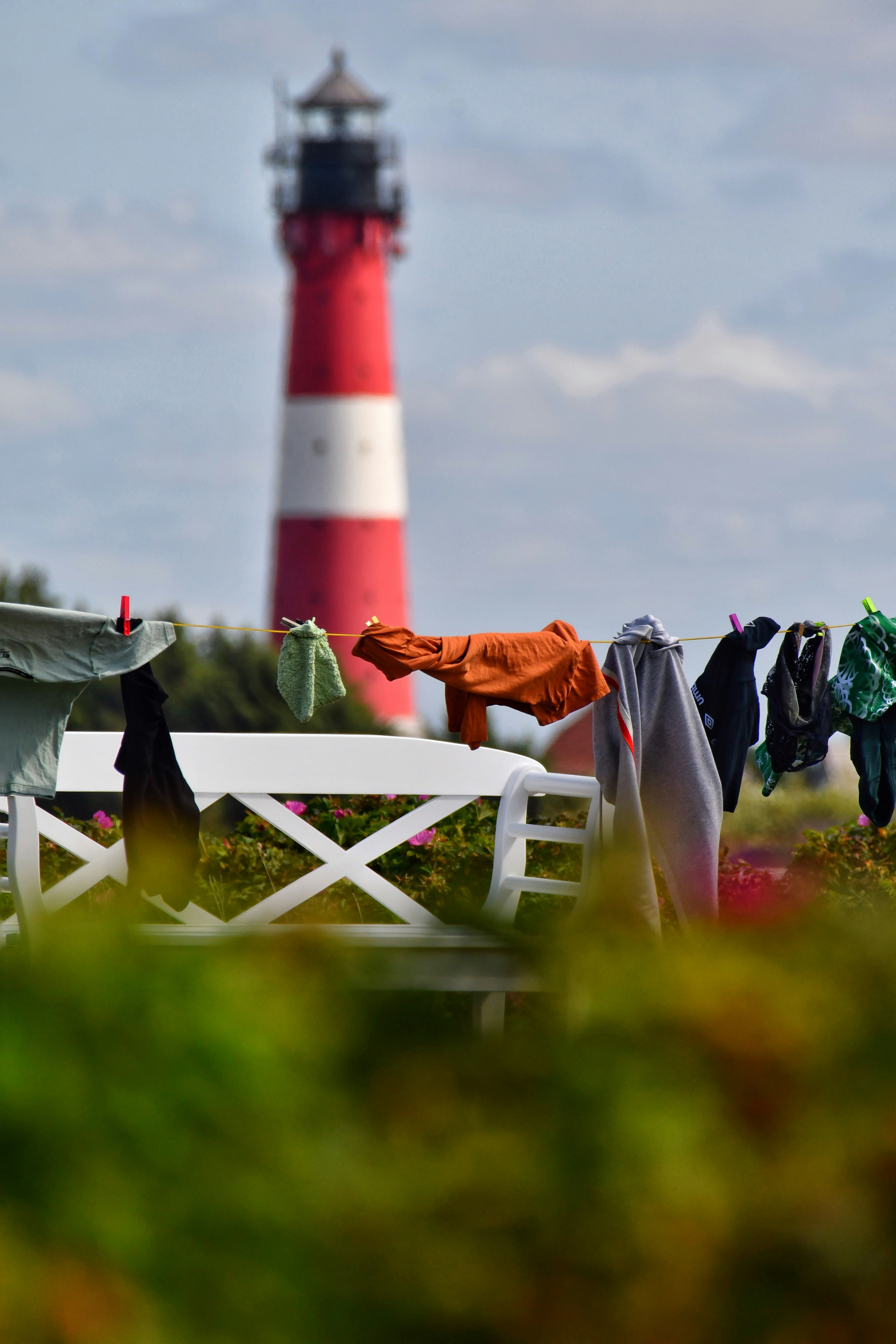 Red Lighthouse in Focus: Clothesline and Bloom in the Foreground